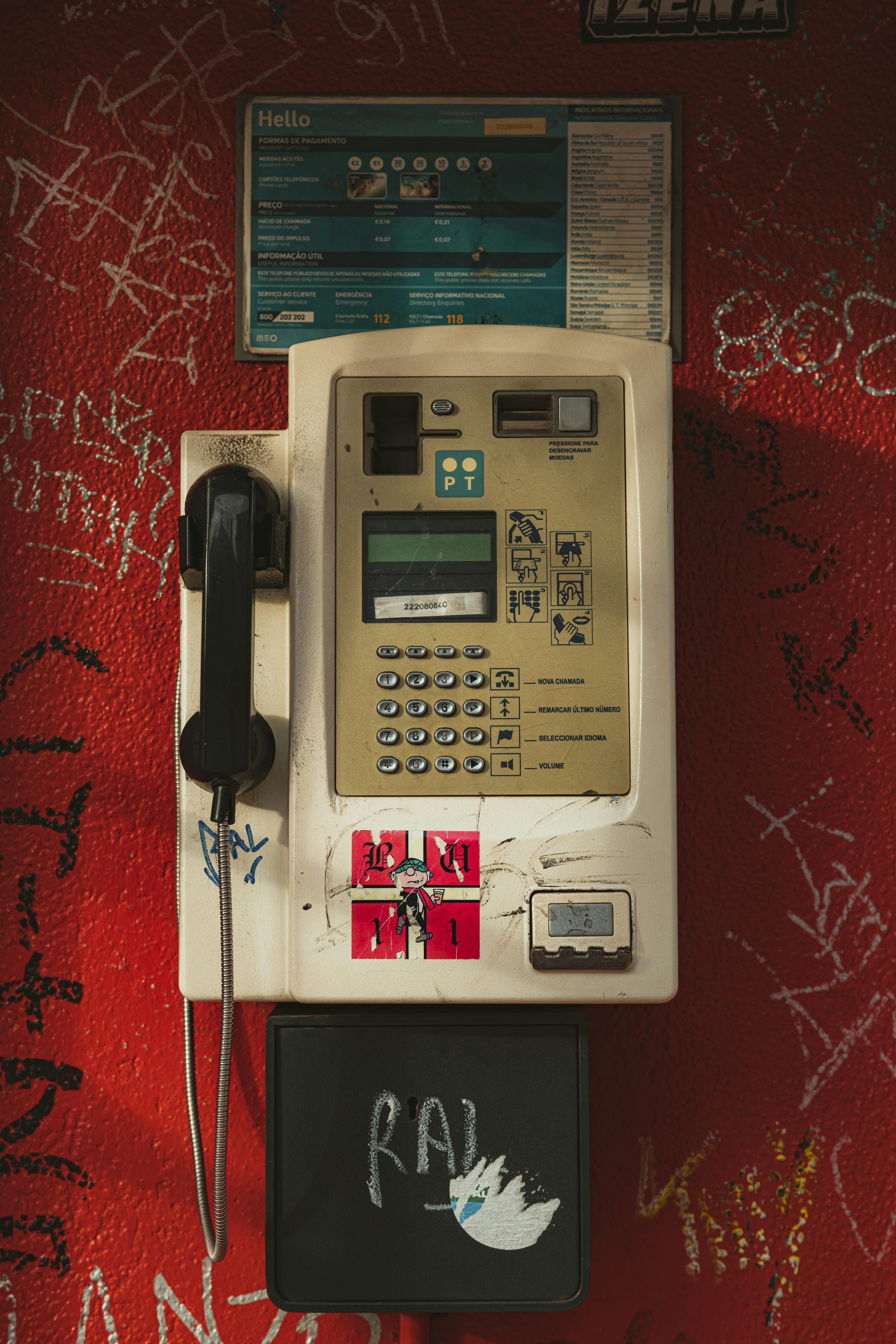 Crimson Graffiti Wall Encloses a Weathered Payphone