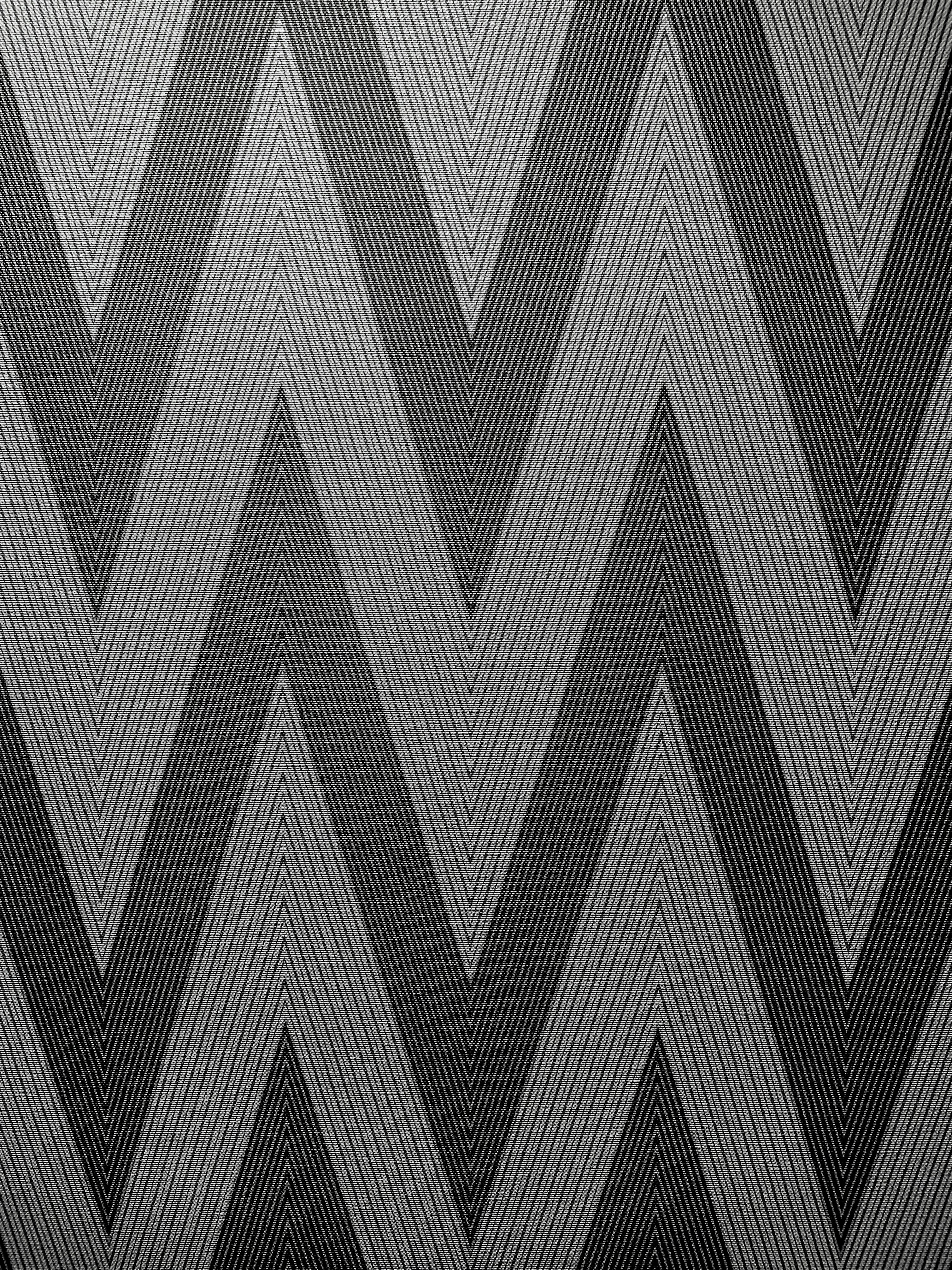 Close-up of a monochrome chevron weave with tightly spaced threads forming zigzag stripes. A fabric pattern showcasing alternating light and dark chevrons.