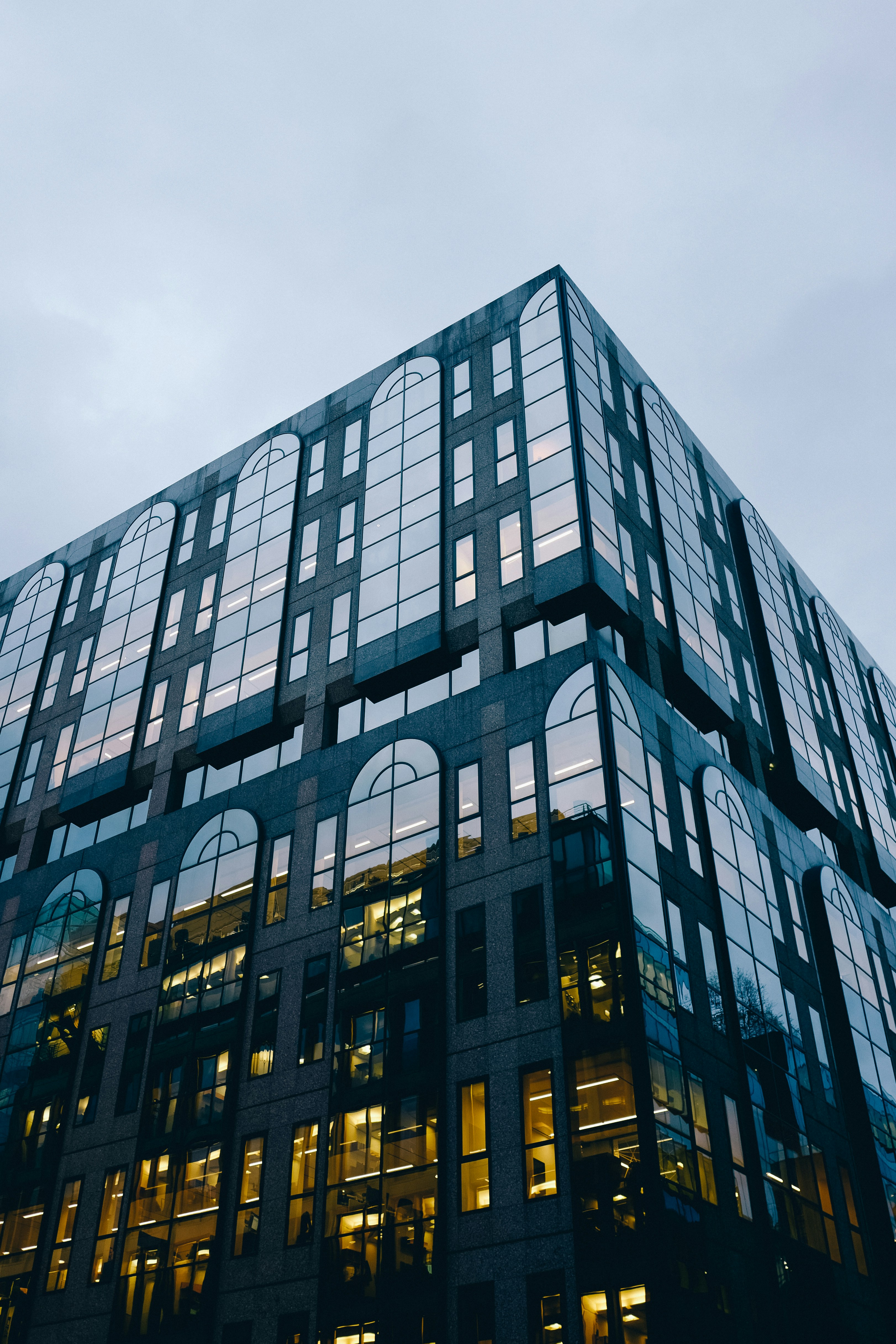 Architectural building with large glass windows reflecting the evening sky, showcasing a blend of modern design and functionality.