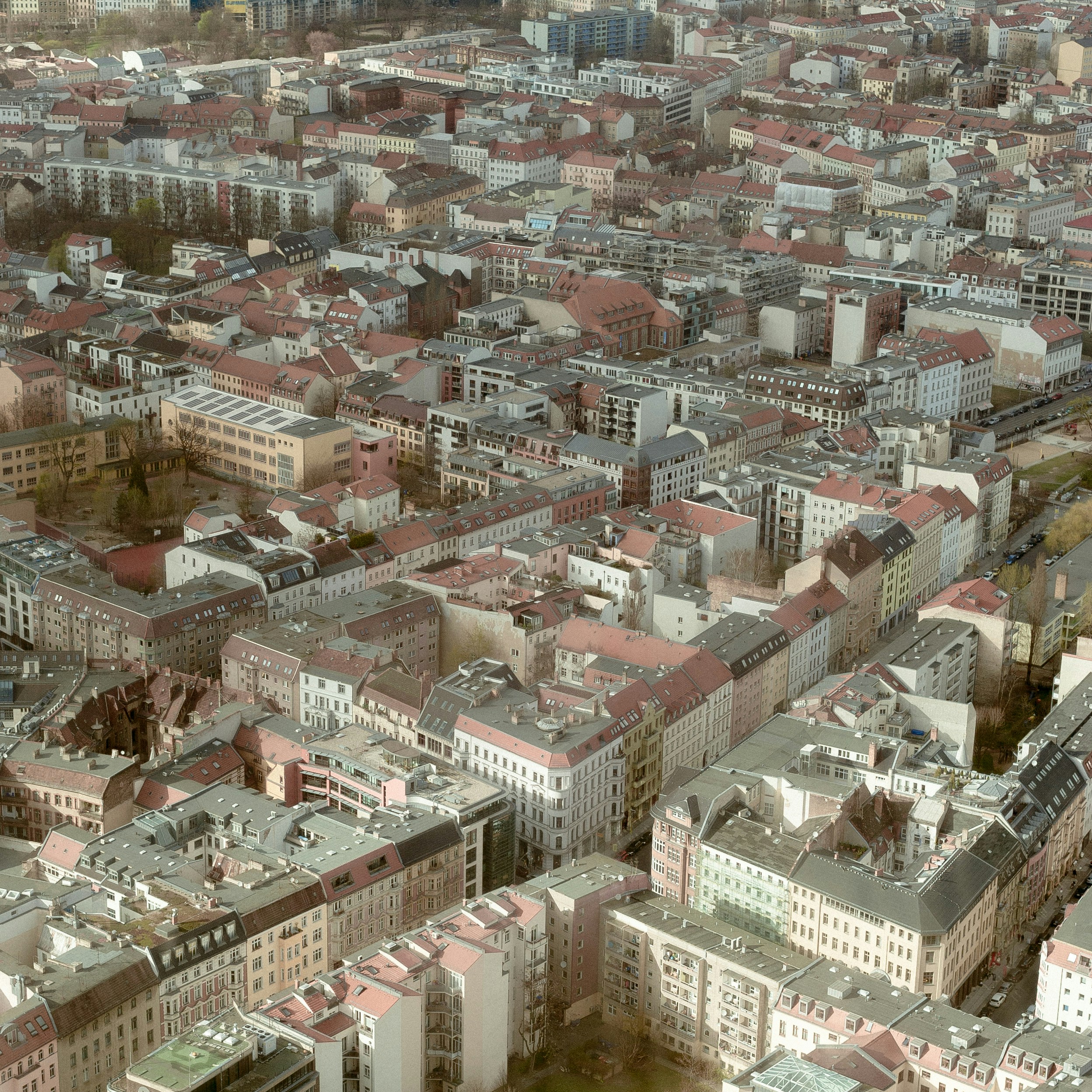 Aerial view showcasing a dense urban landscape with a mix of residential and commercial buildings, revealing the intricate layout of the city. The scene highlights the varied architectural styles and vibrant colors of rooftops.