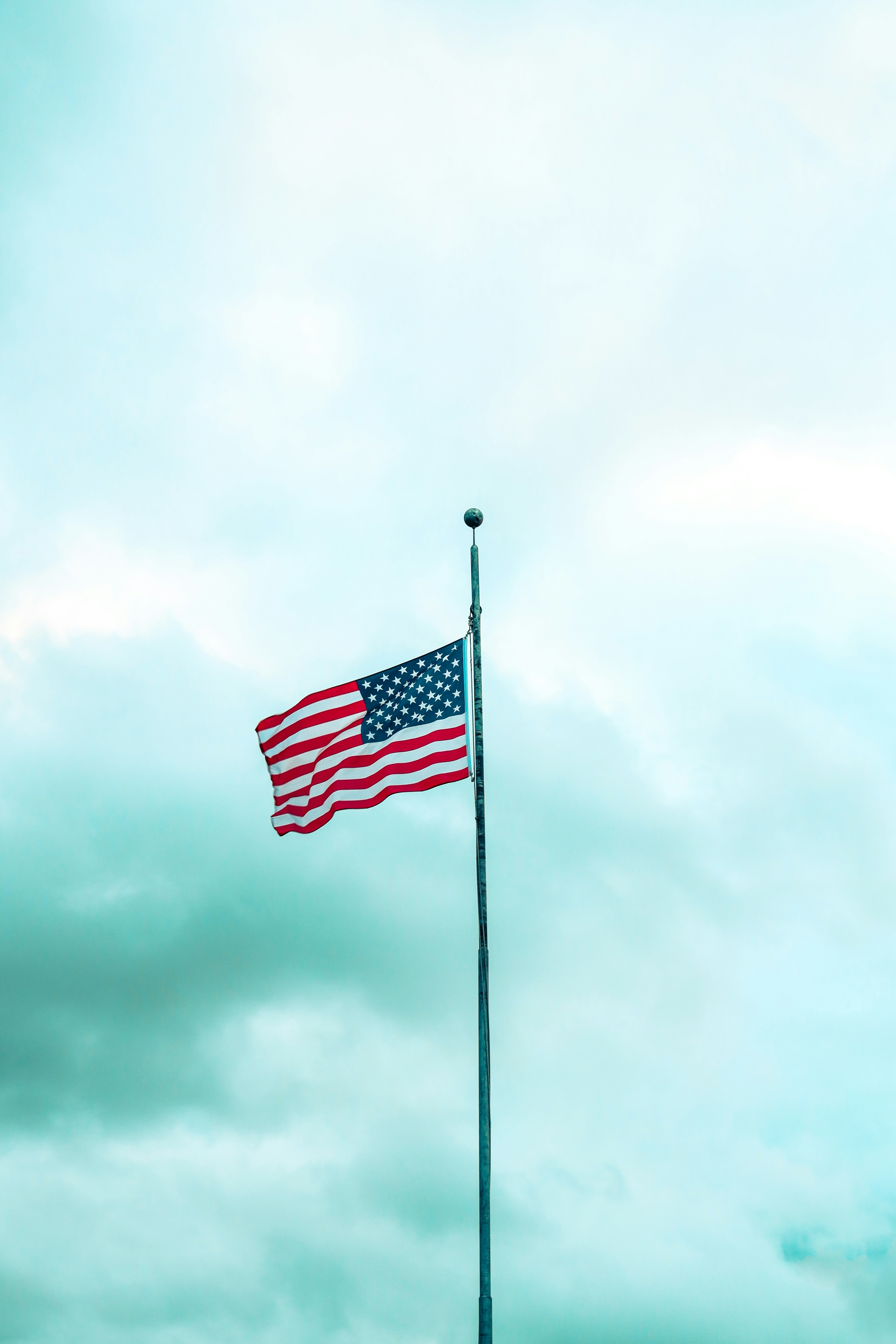 Windward Resolve: American Flag on a Tall Pole Beneath a Cloudy Sky