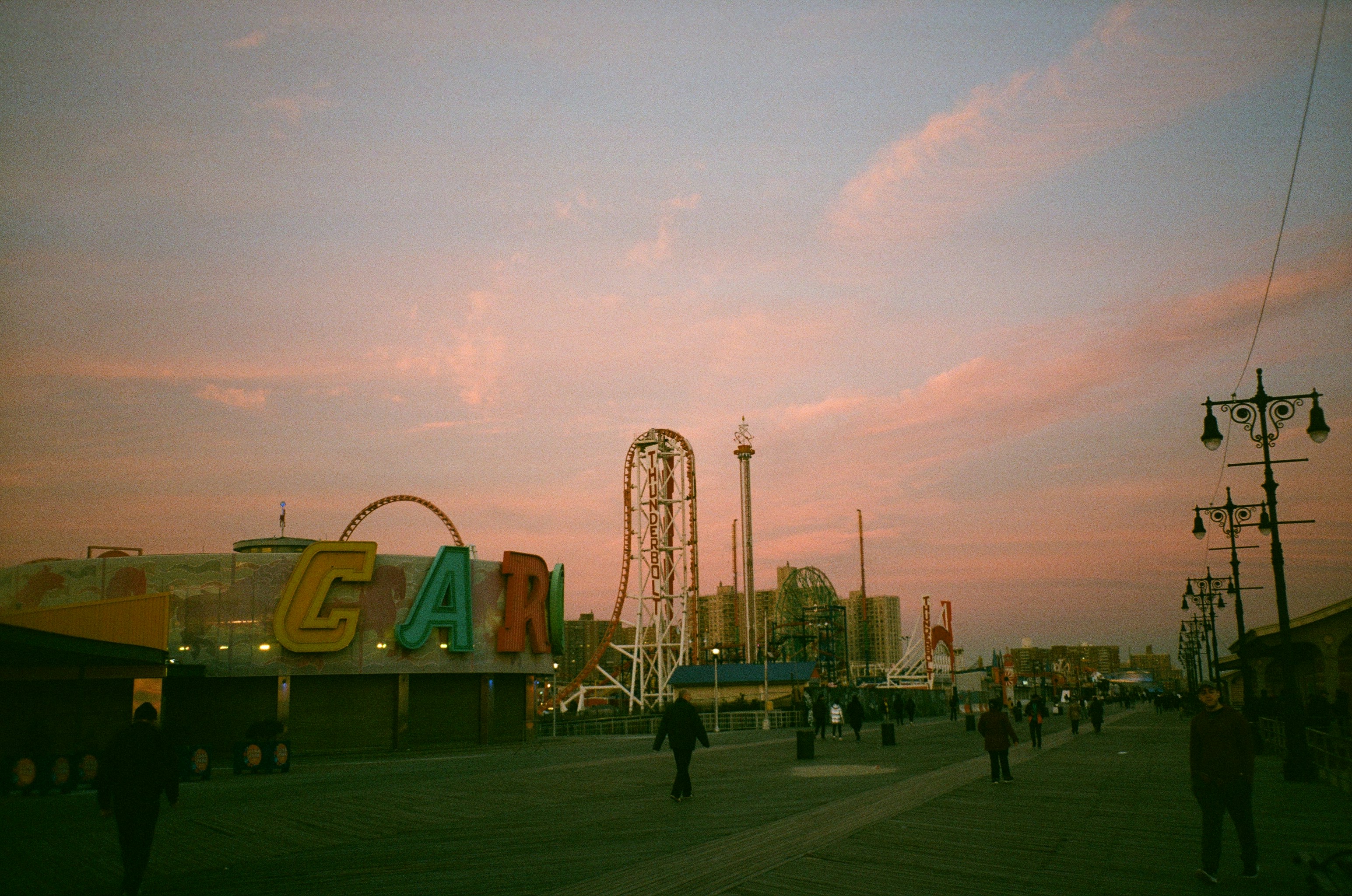 Dusk Boardwalk: Neon Signage and Distant Roller Coaster Silhouettes