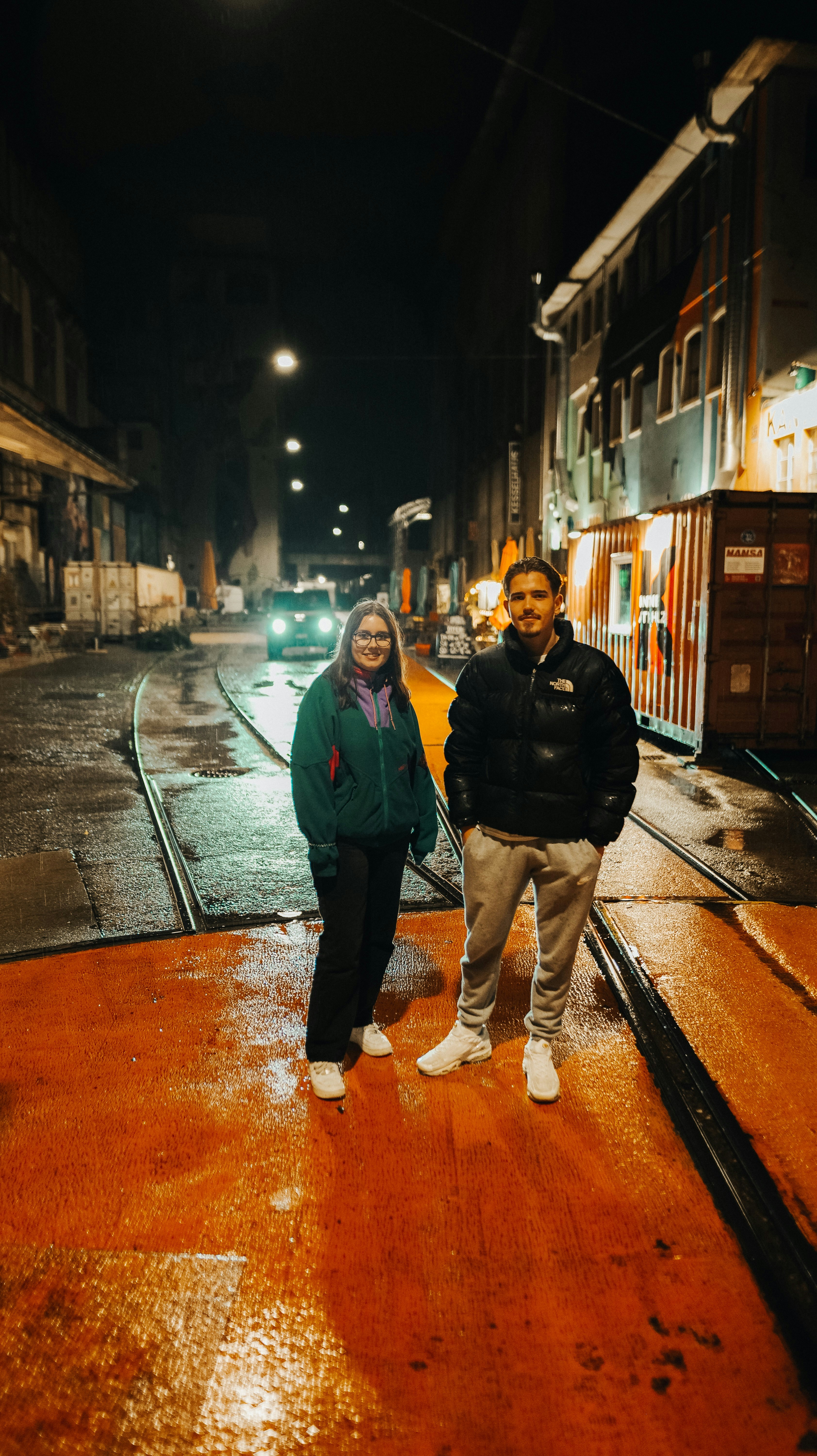 Night Crossing: Friends Stand Amid City Rail in Warm Glow