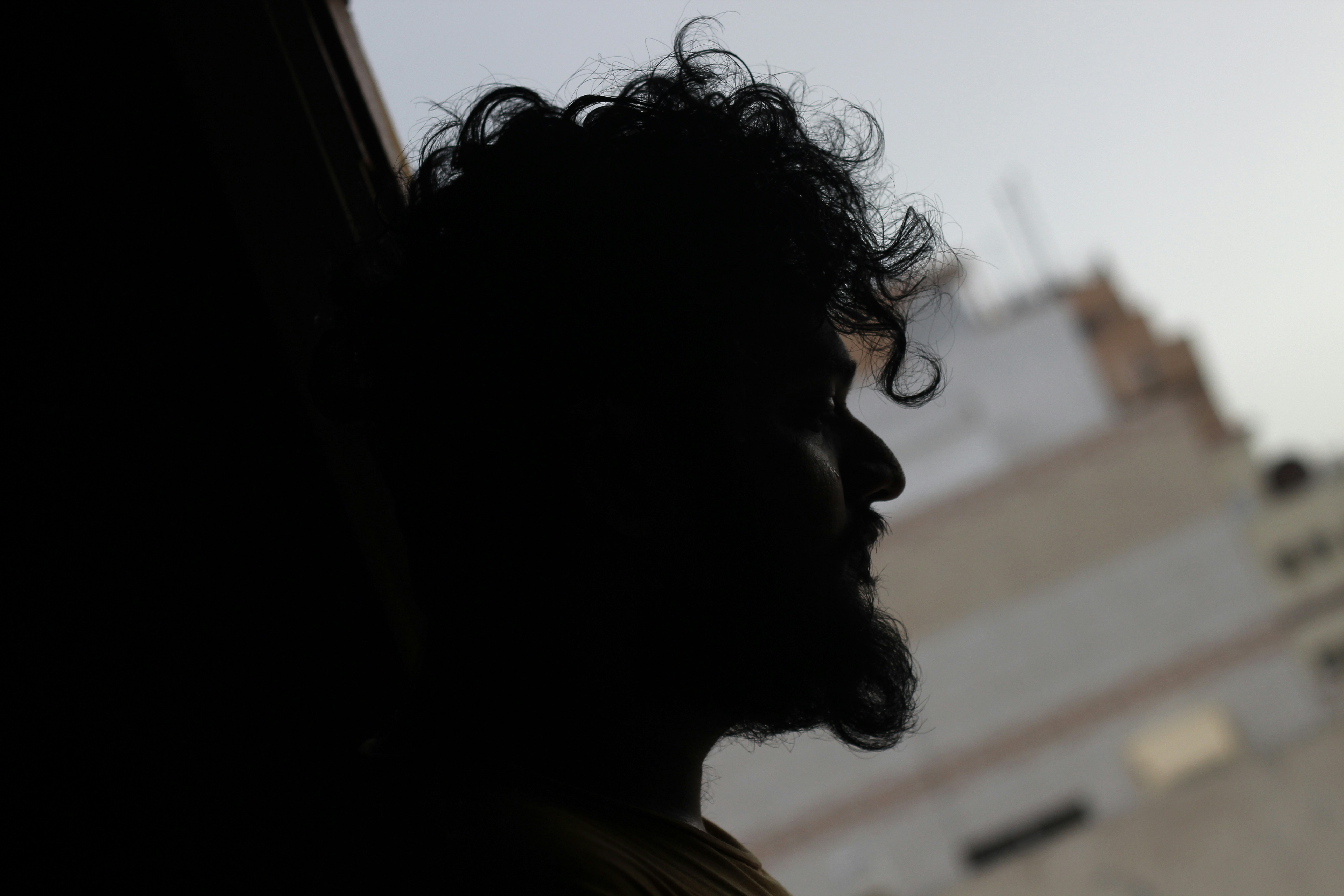 Bearded Silhouette at Window Light Over a Quiet Cityscape