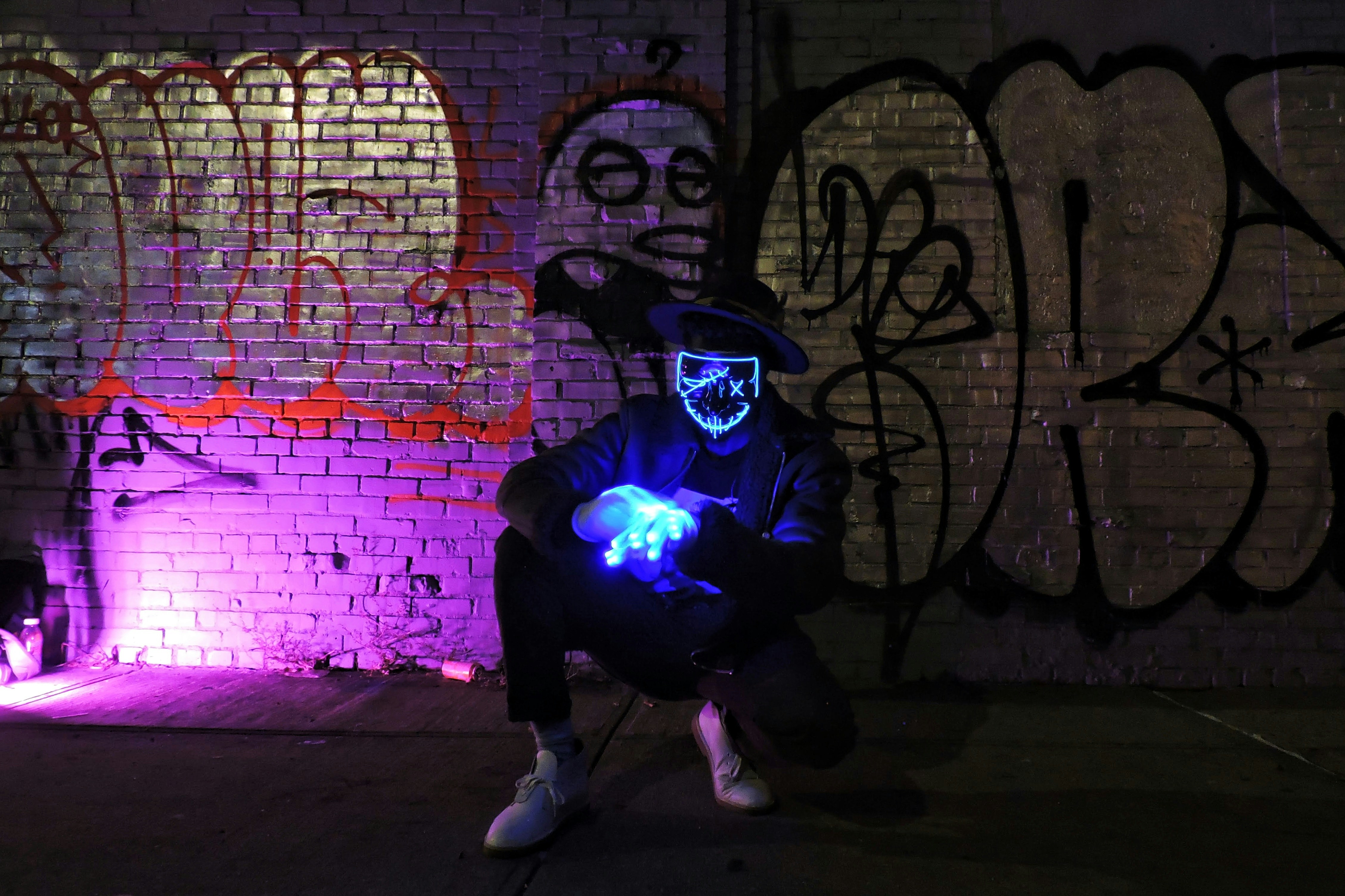 Neon-lit Graffiti Night: A Hooded Figure Sparks Blue Glow