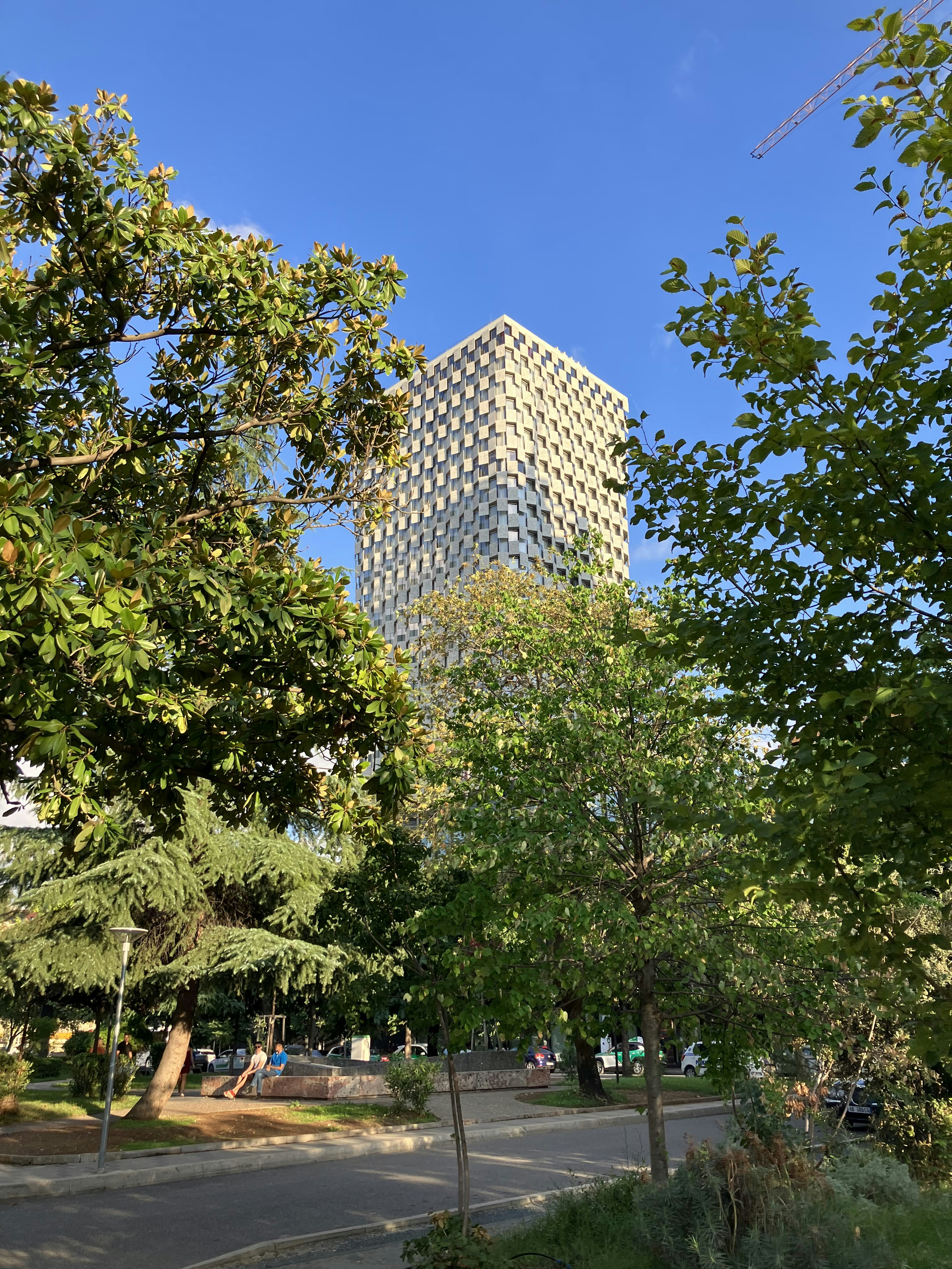 A tall building behind trees photo – Free Tirana Image on Unsplash