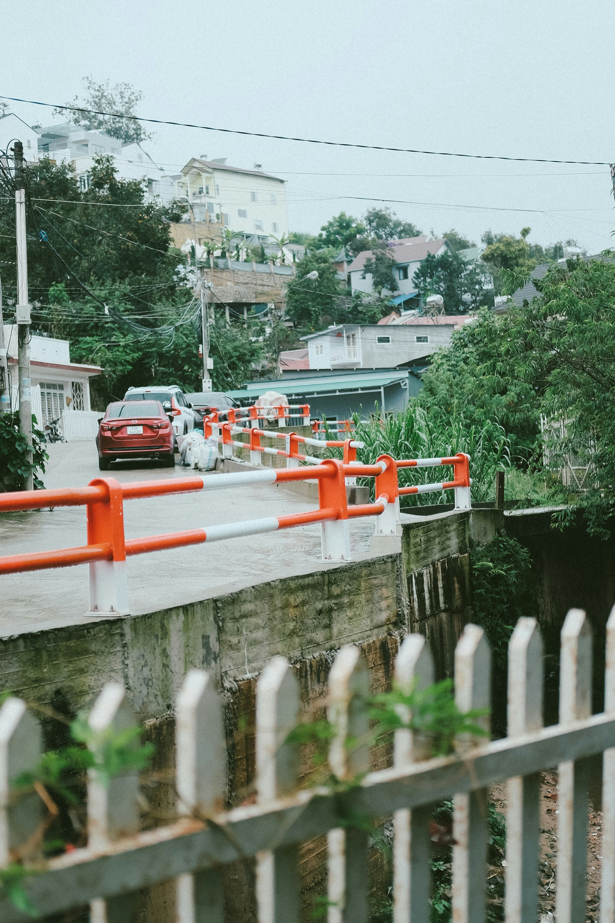 Crimson Car on a Hilltop Street Framed by Orange Guard Rails