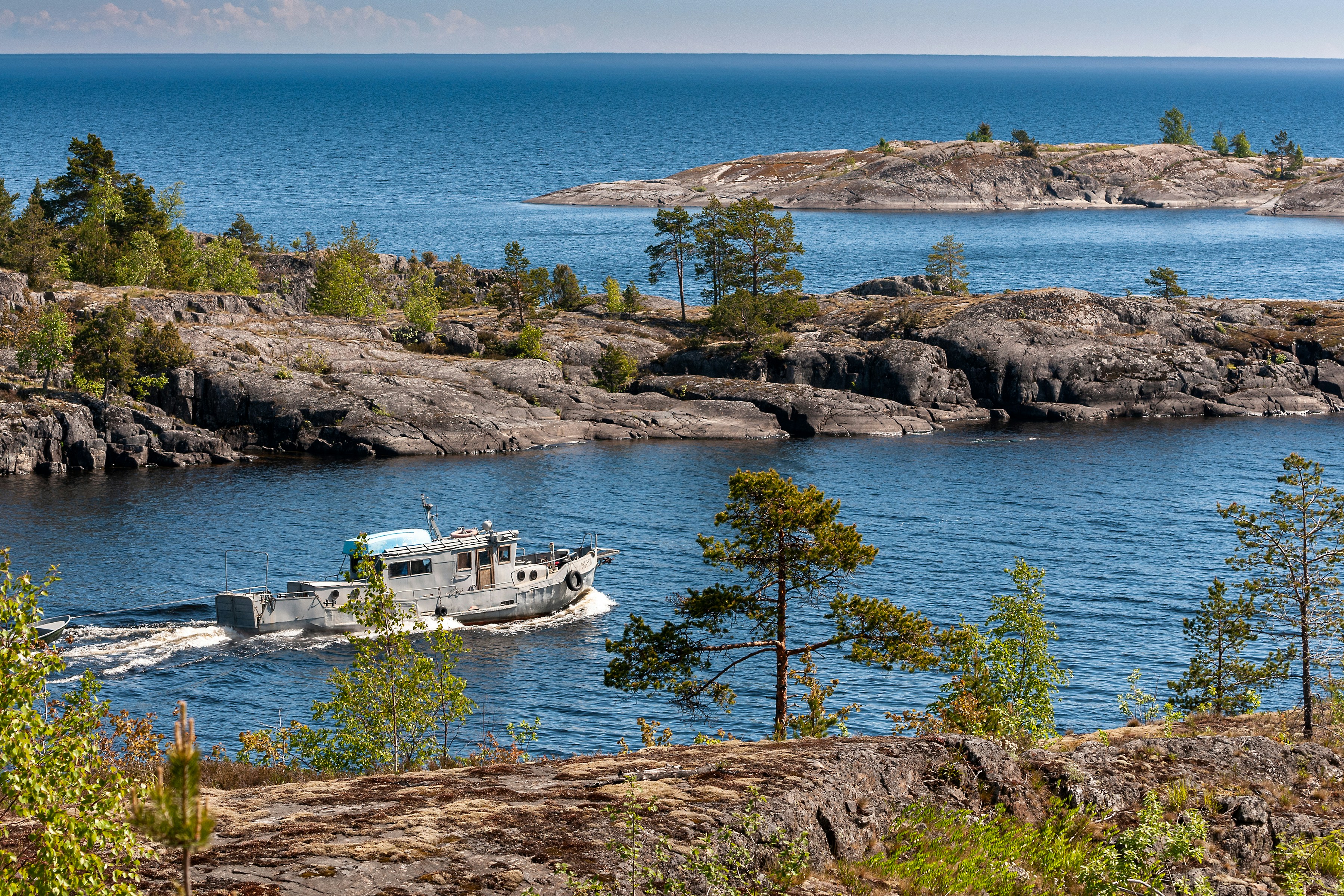 A boat navigates through tranquil waters surrounded by rugged islands and lush greenery, highlighting the harmony of nature and human activity.