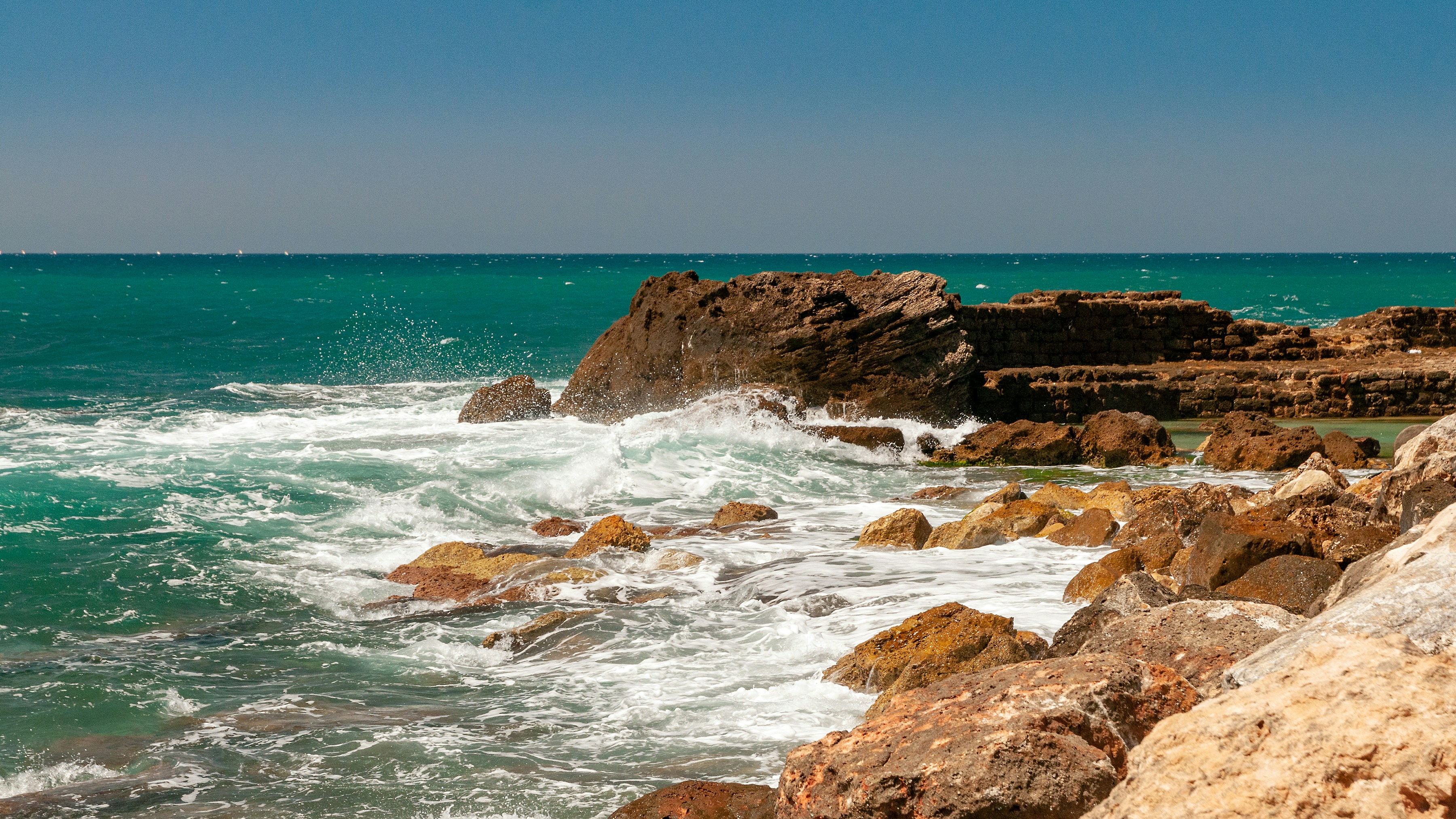 Ein felsiger Strand mit Wellen, die gegen ihn prallen Foto ...