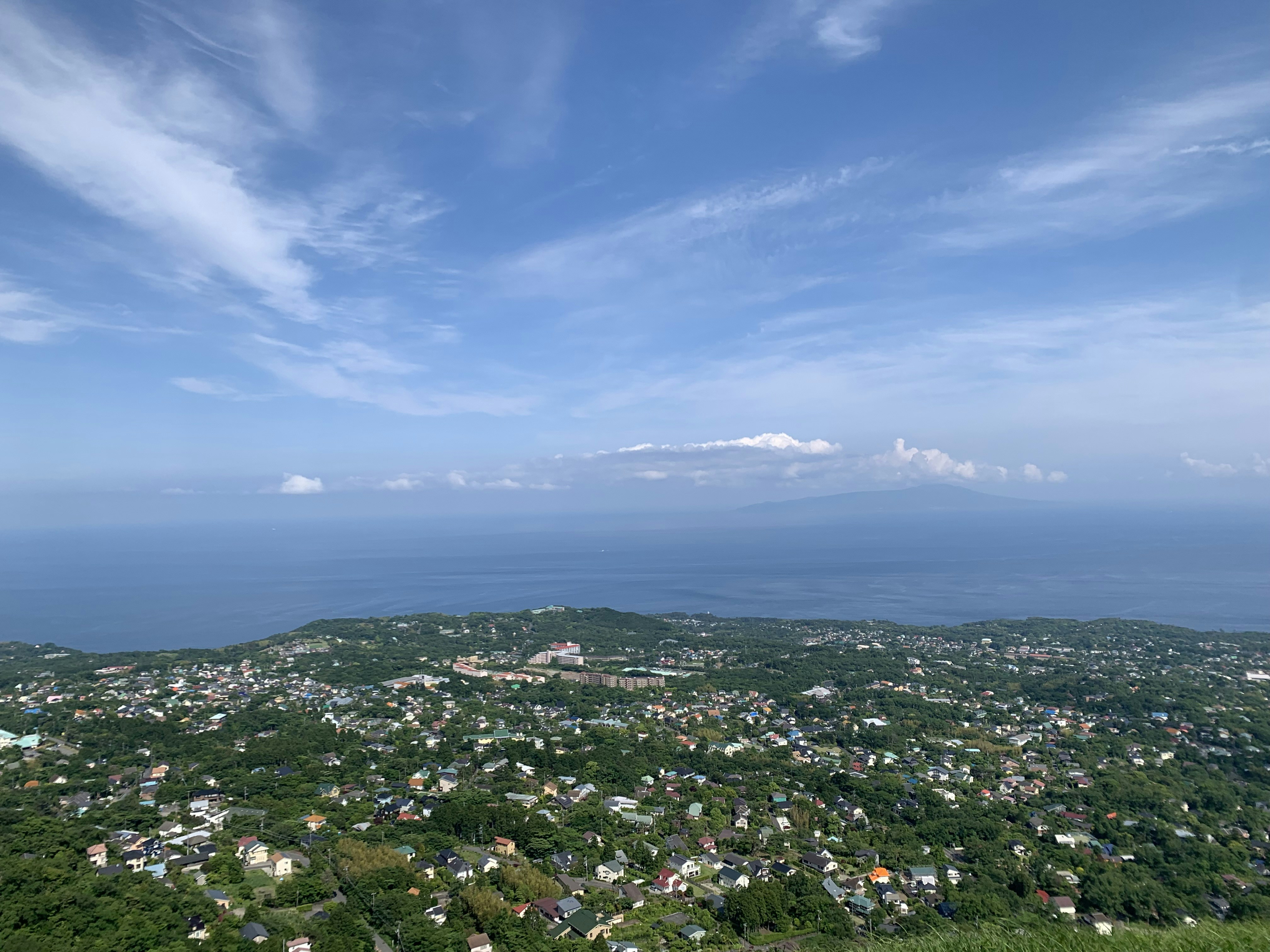 Coastal hillside town: rooftops, green mosaic toward the open sea