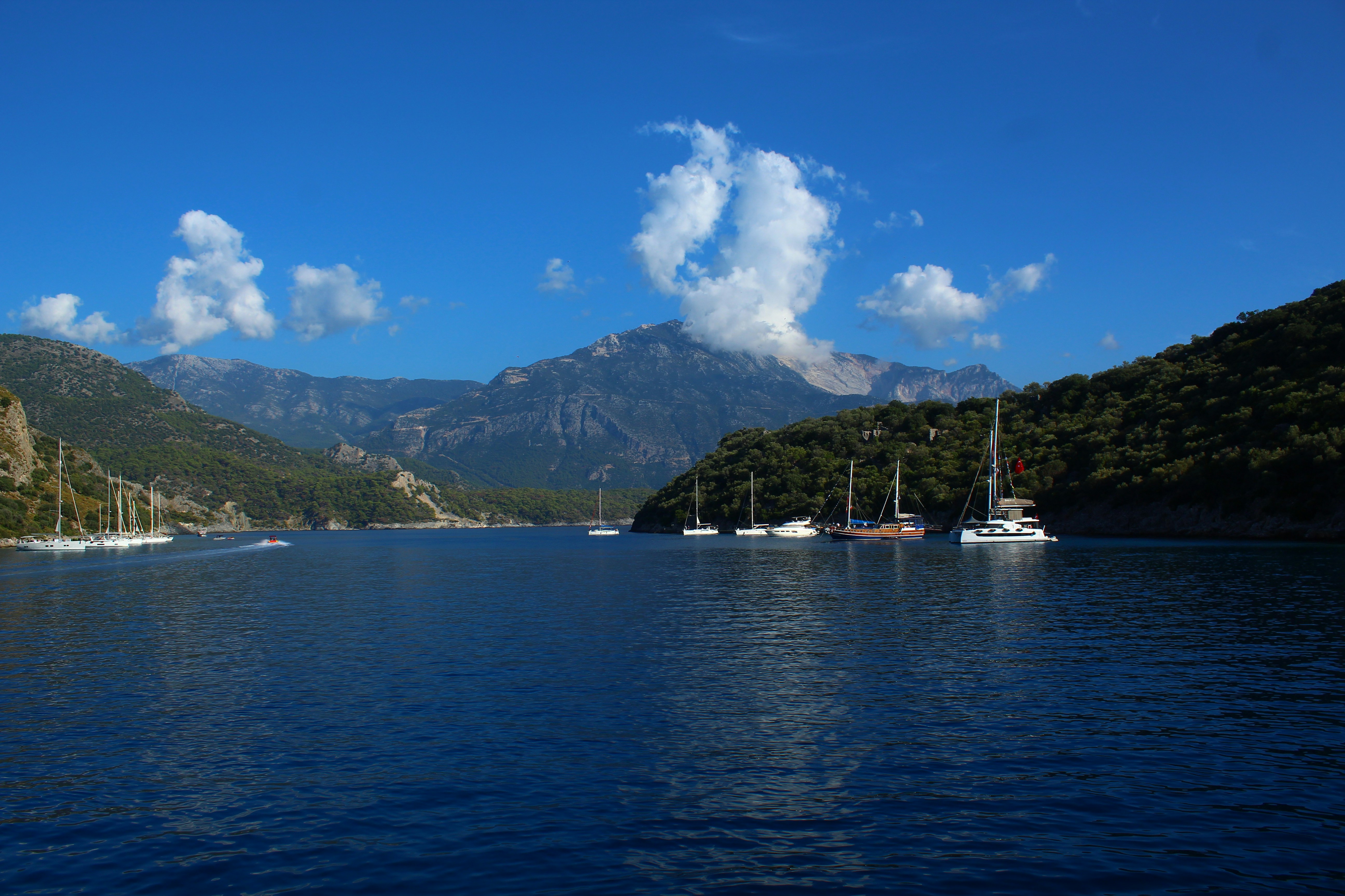 Azure Inlet: Anchored Sails Framed by Mountain Outlines