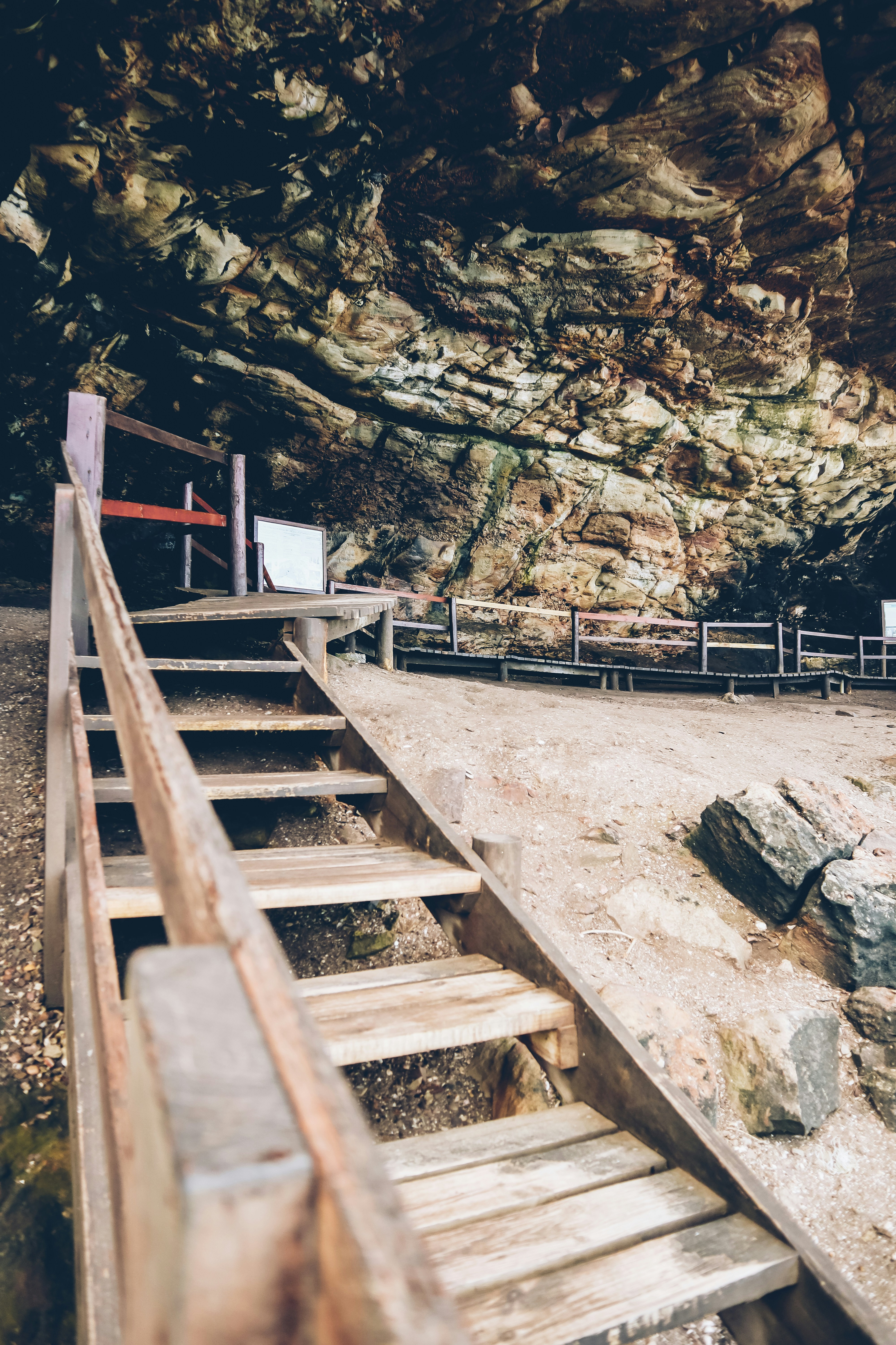 Wooden stairs lead into a cavernous space, revealing textured rock walls and a sense of adventure.
