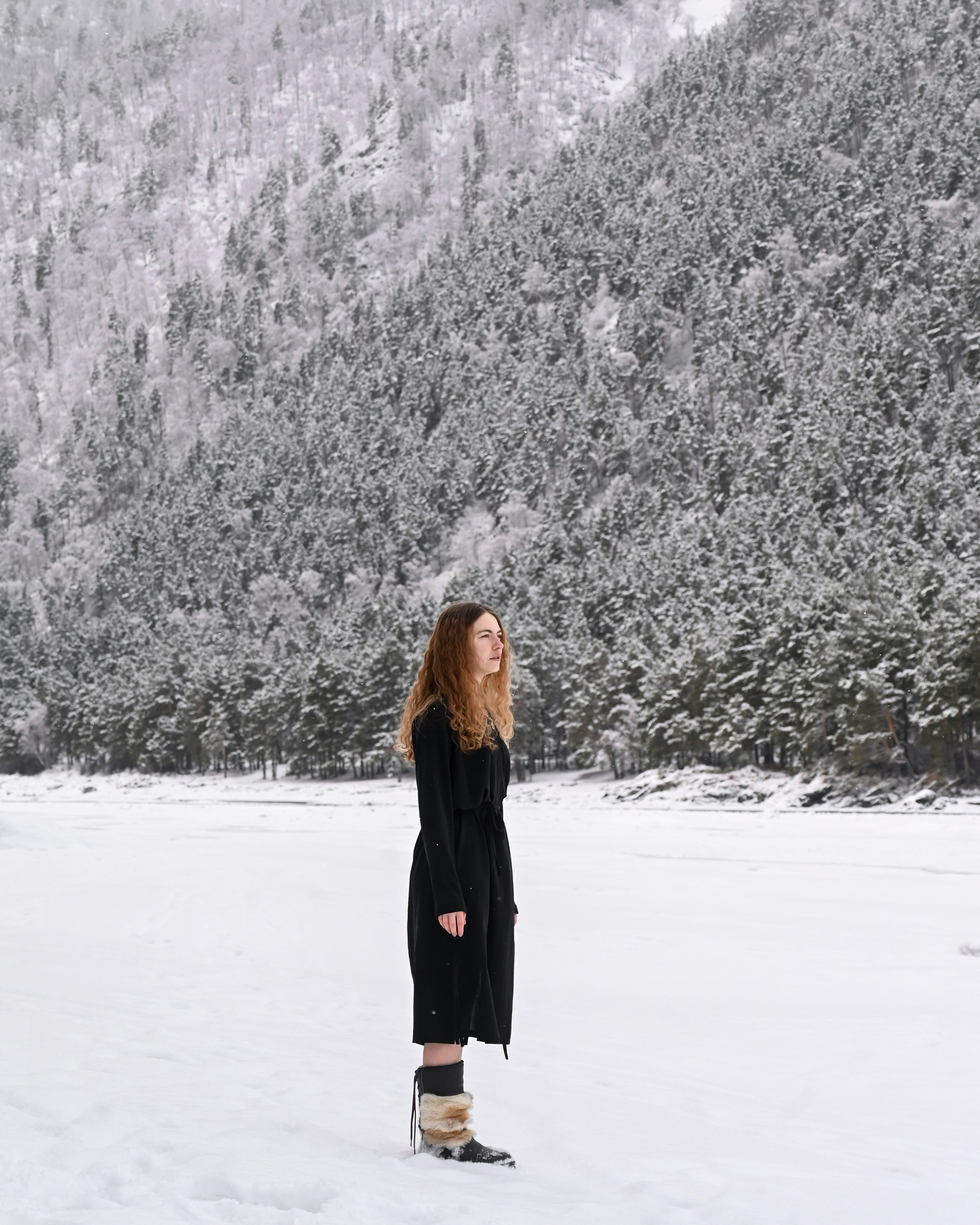 Lone Winter Portrait: A Woman Stands in a Snowbound Clearing Beneath Frosted Pines