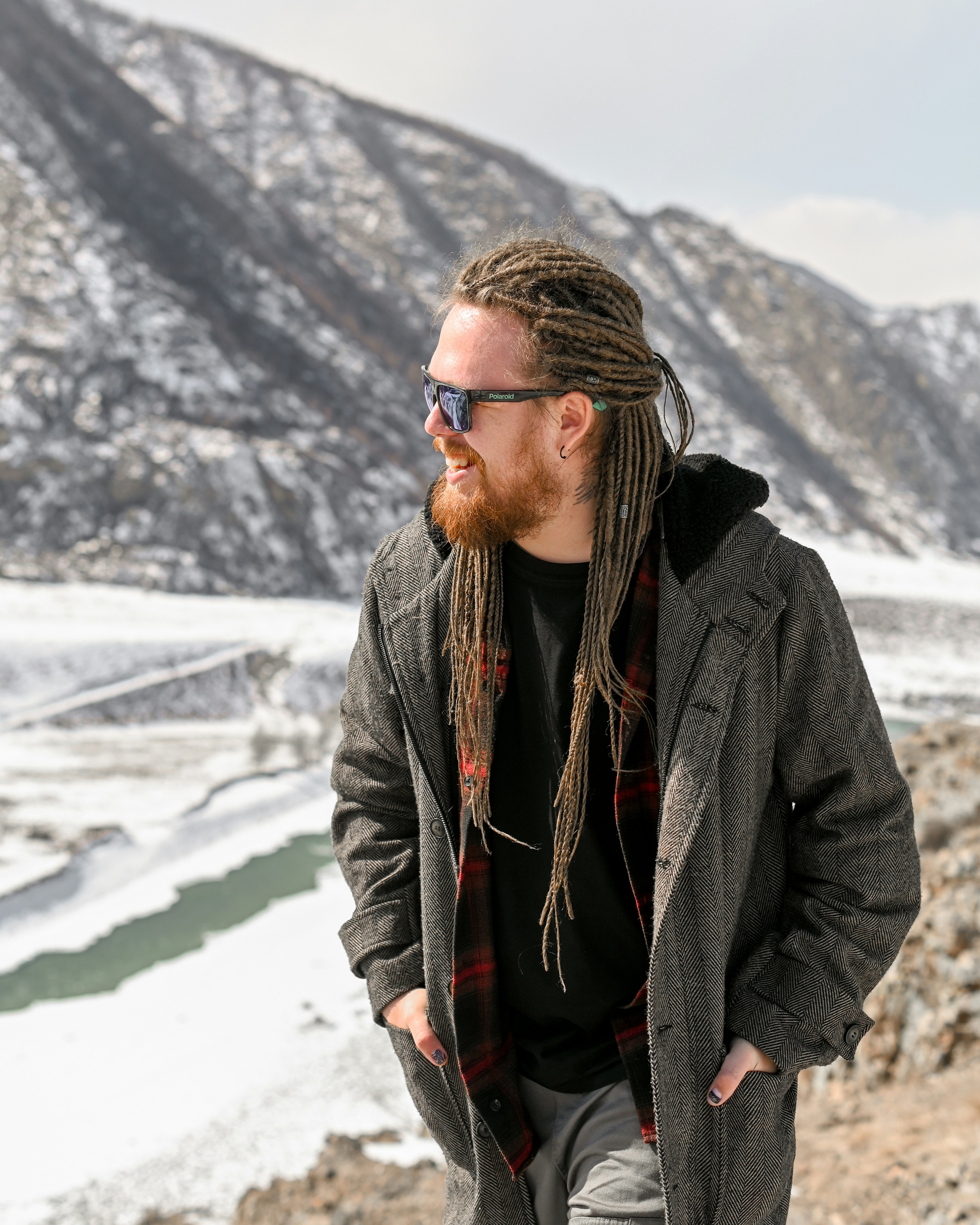 Snowbound Portrait: Bearded Traveler with Dreadlocks Against Icy Peaks