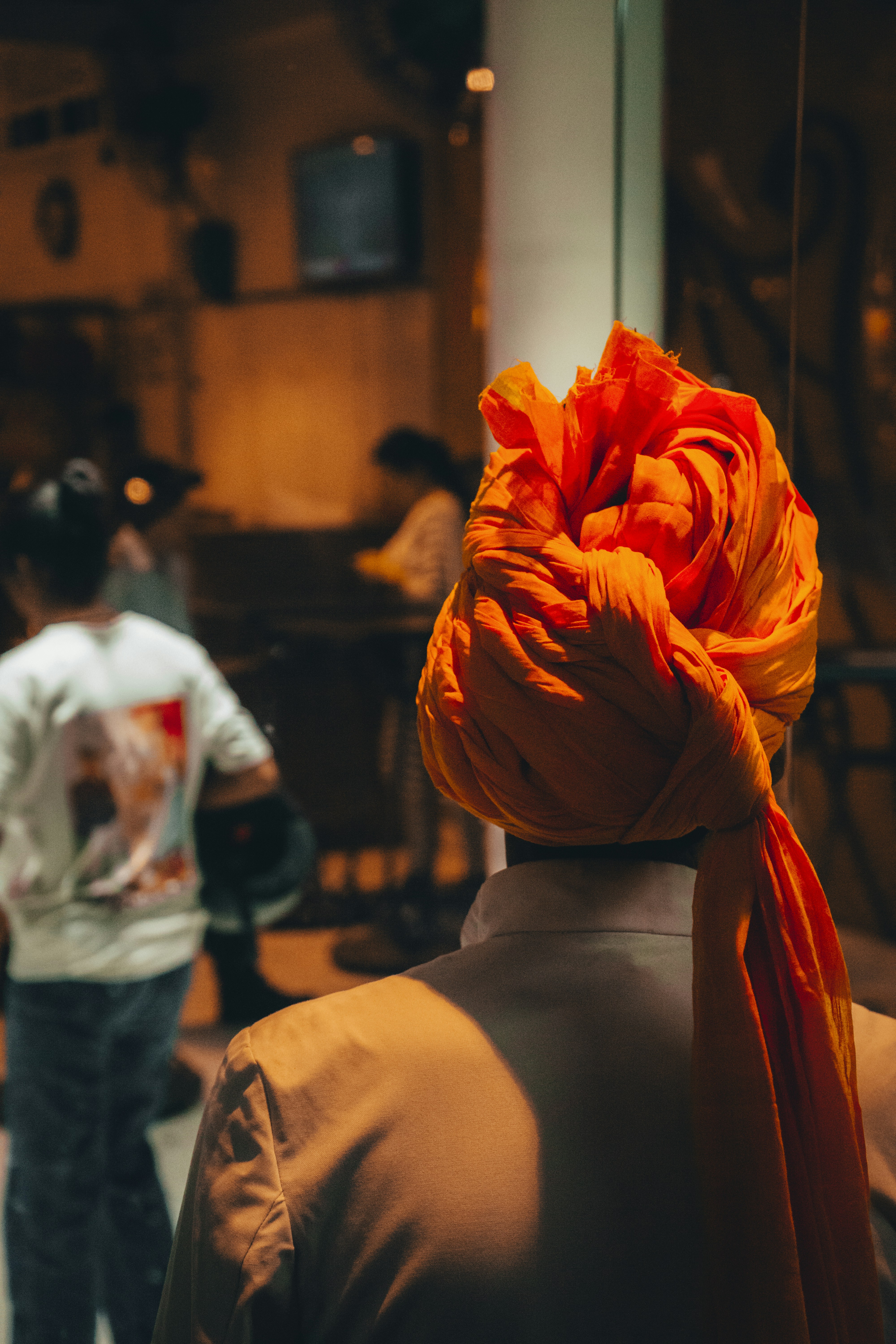 Orange Turban, Quiet Converse: A Street Portrait in Warm Light