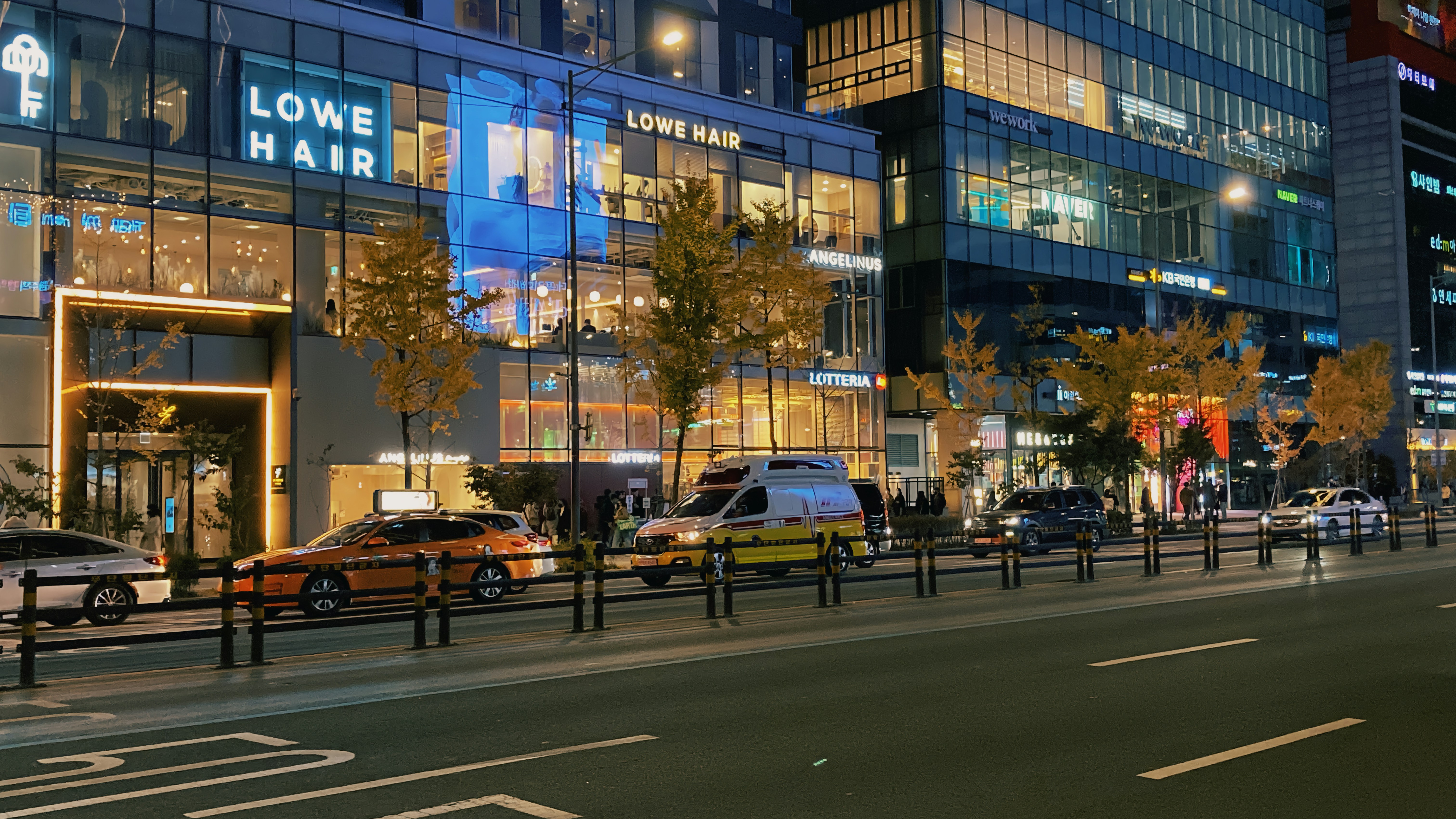 Vibrant city scene featuring illuminated storefronts and bustling traffic under evening lights.