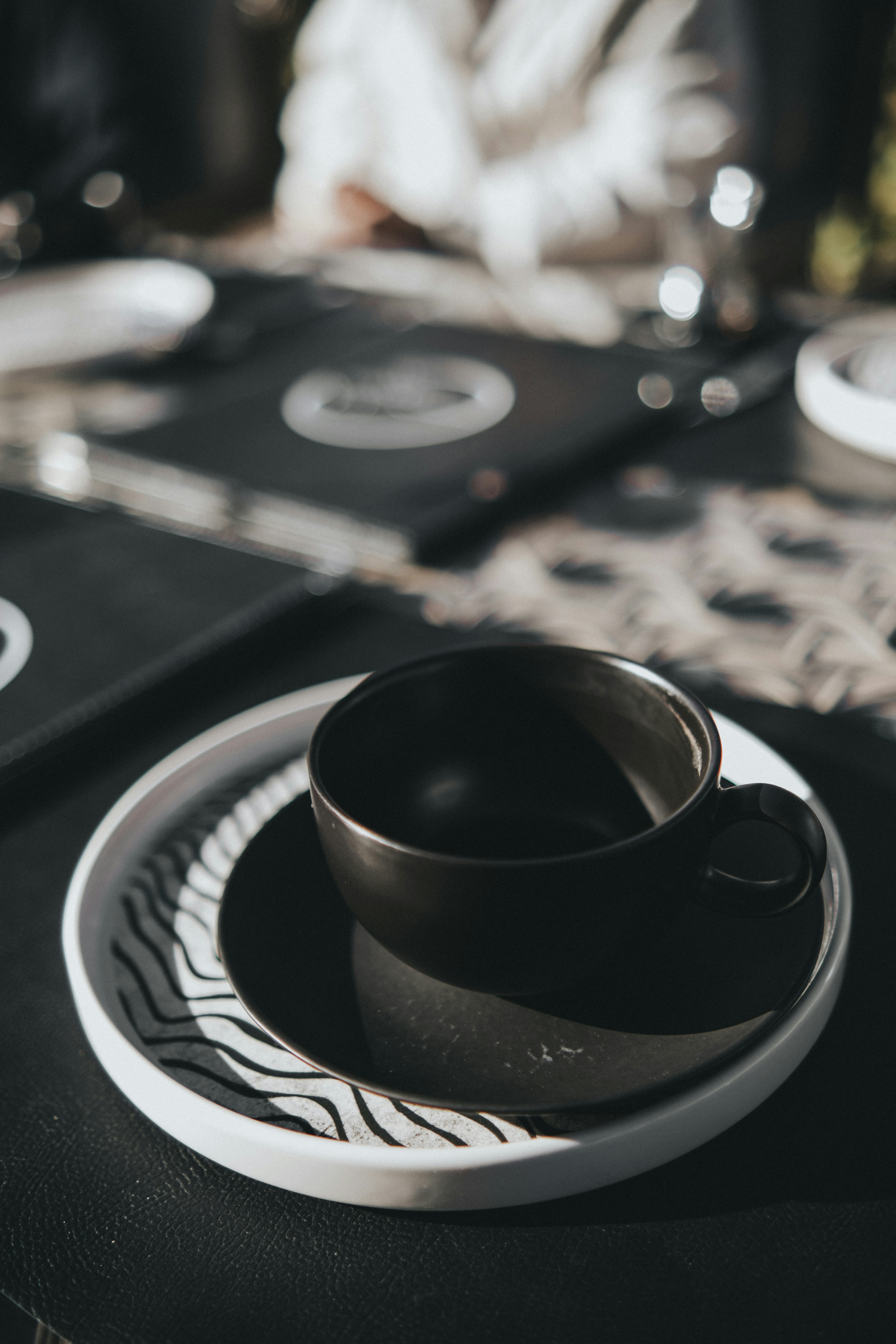 Midday Stillness: A Black Cup Resting on a Zebra-Striped Plate