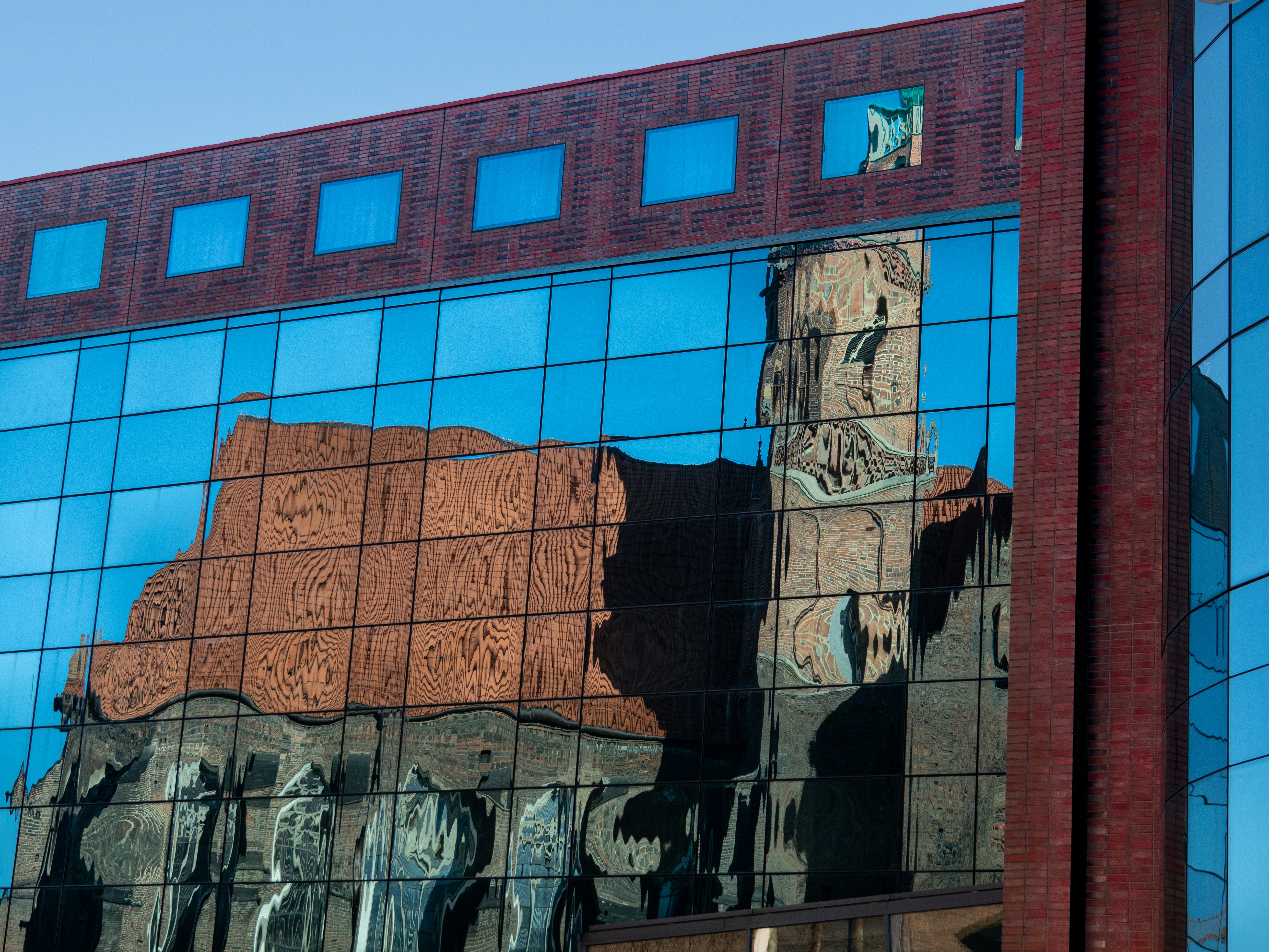Tower Reflections Woven Through a Glass and Brick Facade