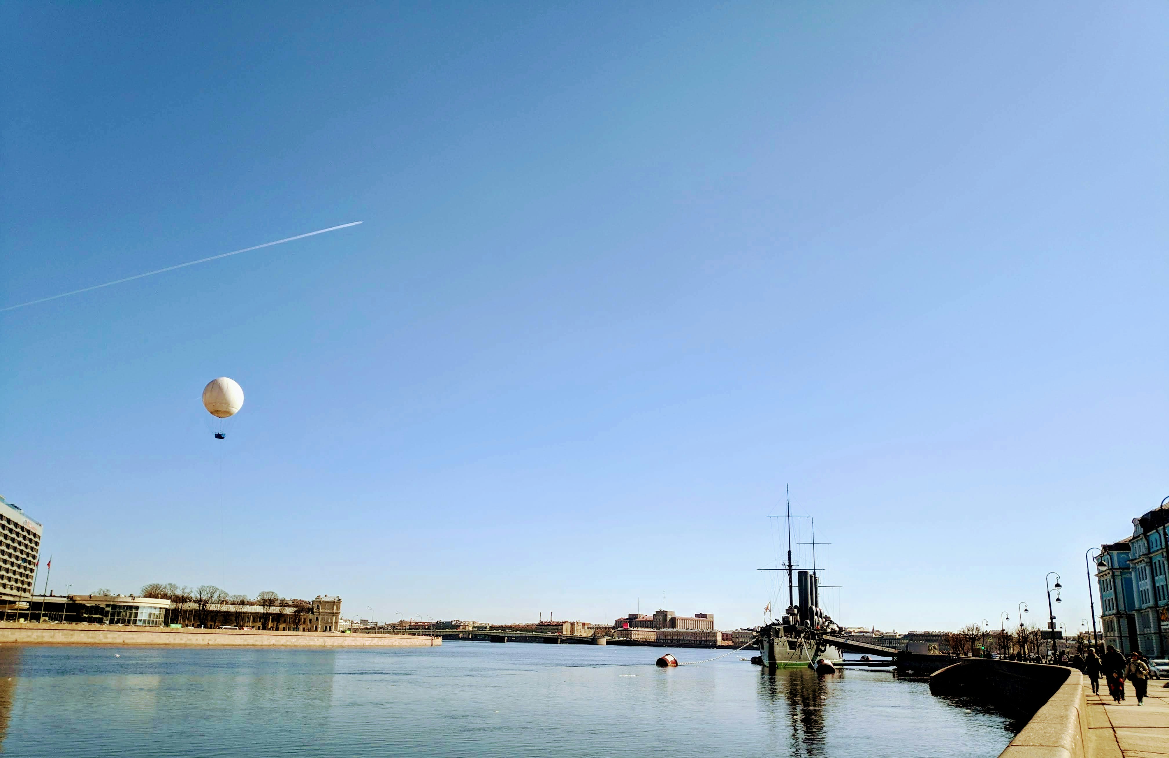 Balloon over the Blue Harbor: a lone drift above calm water by the quay