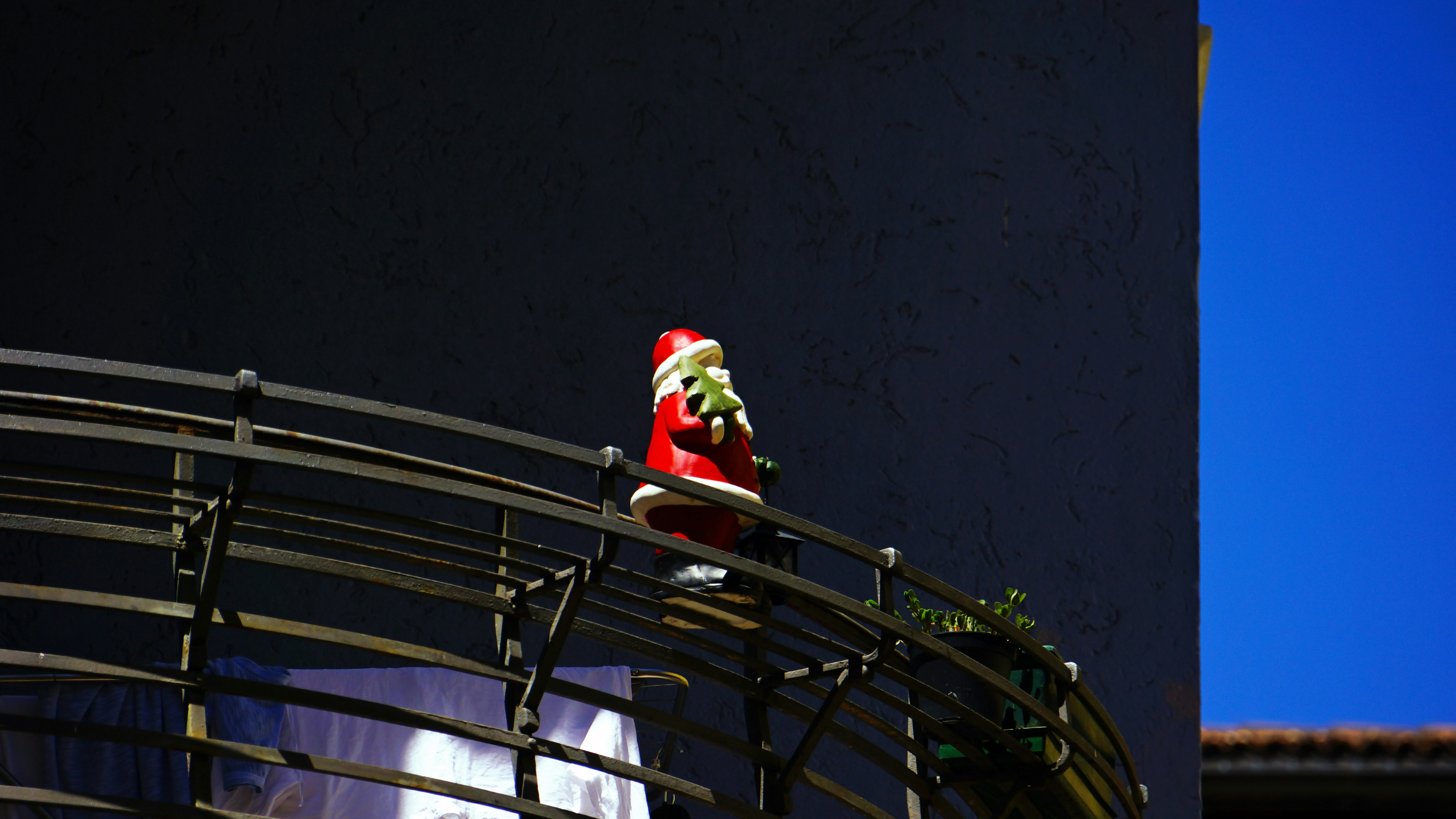 Santa on the Balcony: A Festive Silhouette Against a Clear Blue Sky