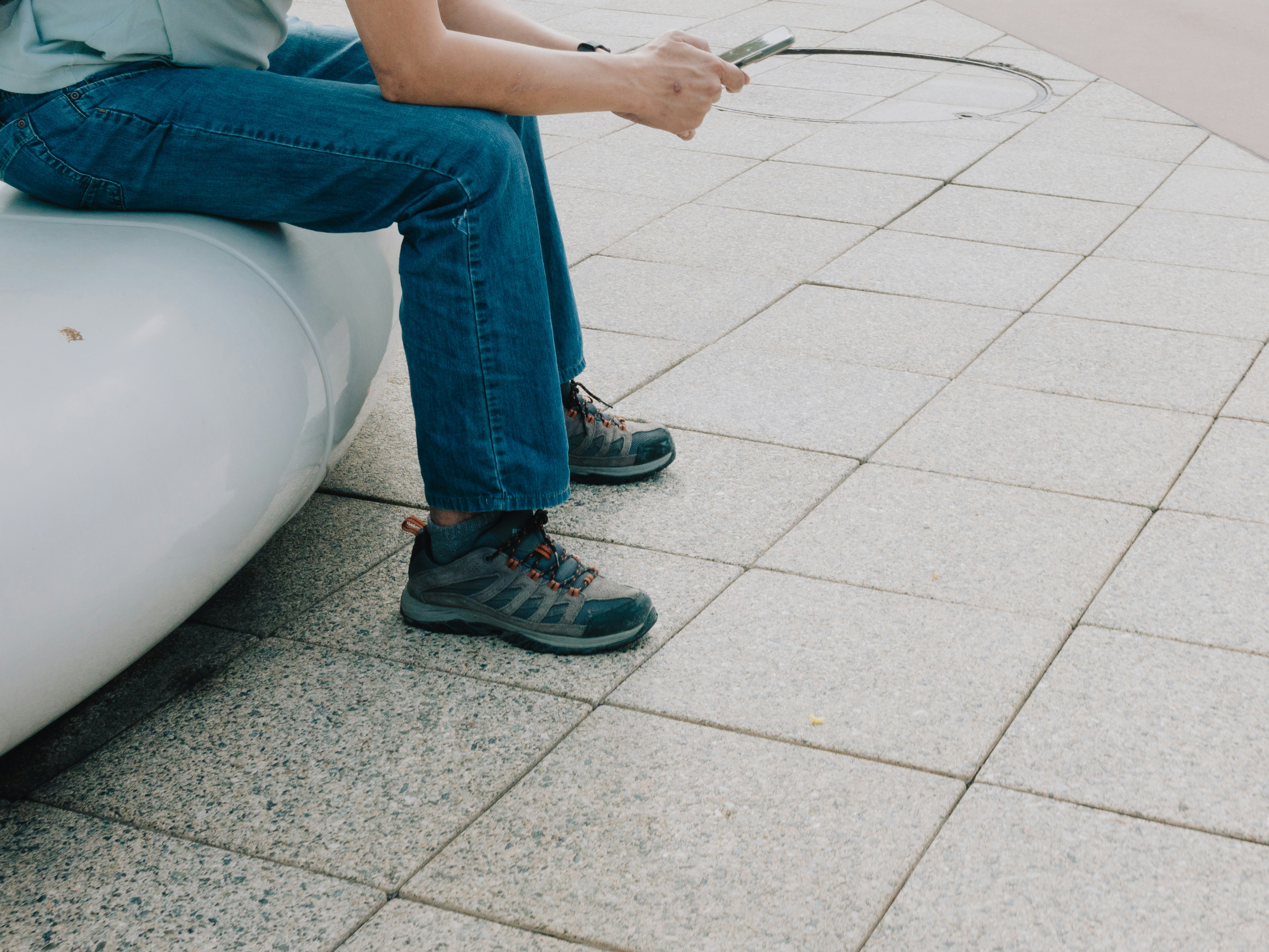 Paused Hands: A Quiet Moment with a Slim Device on a Curved Bench