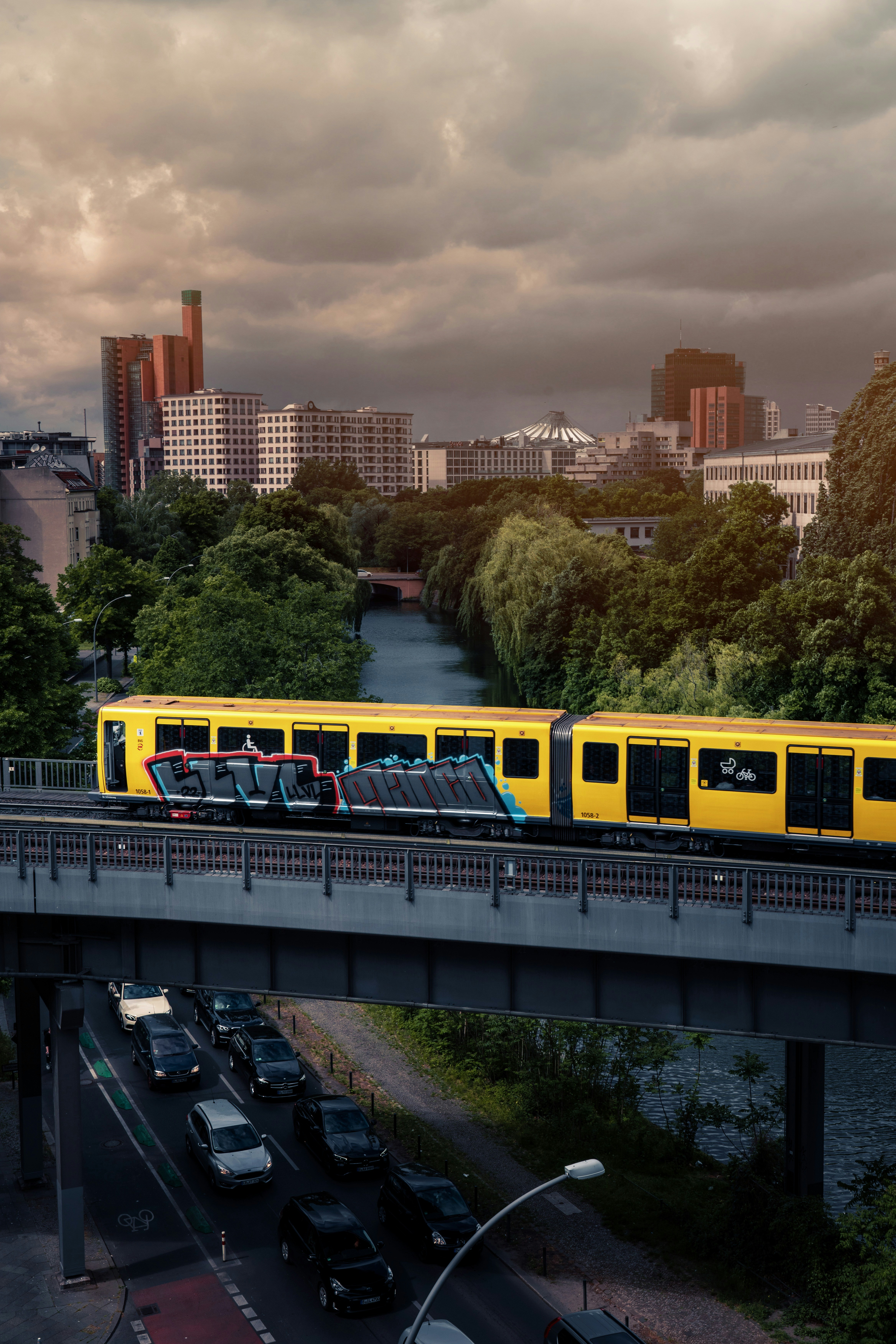 Graffiti-Tagged Yellow Train Crossing a River Bridge at Dusk