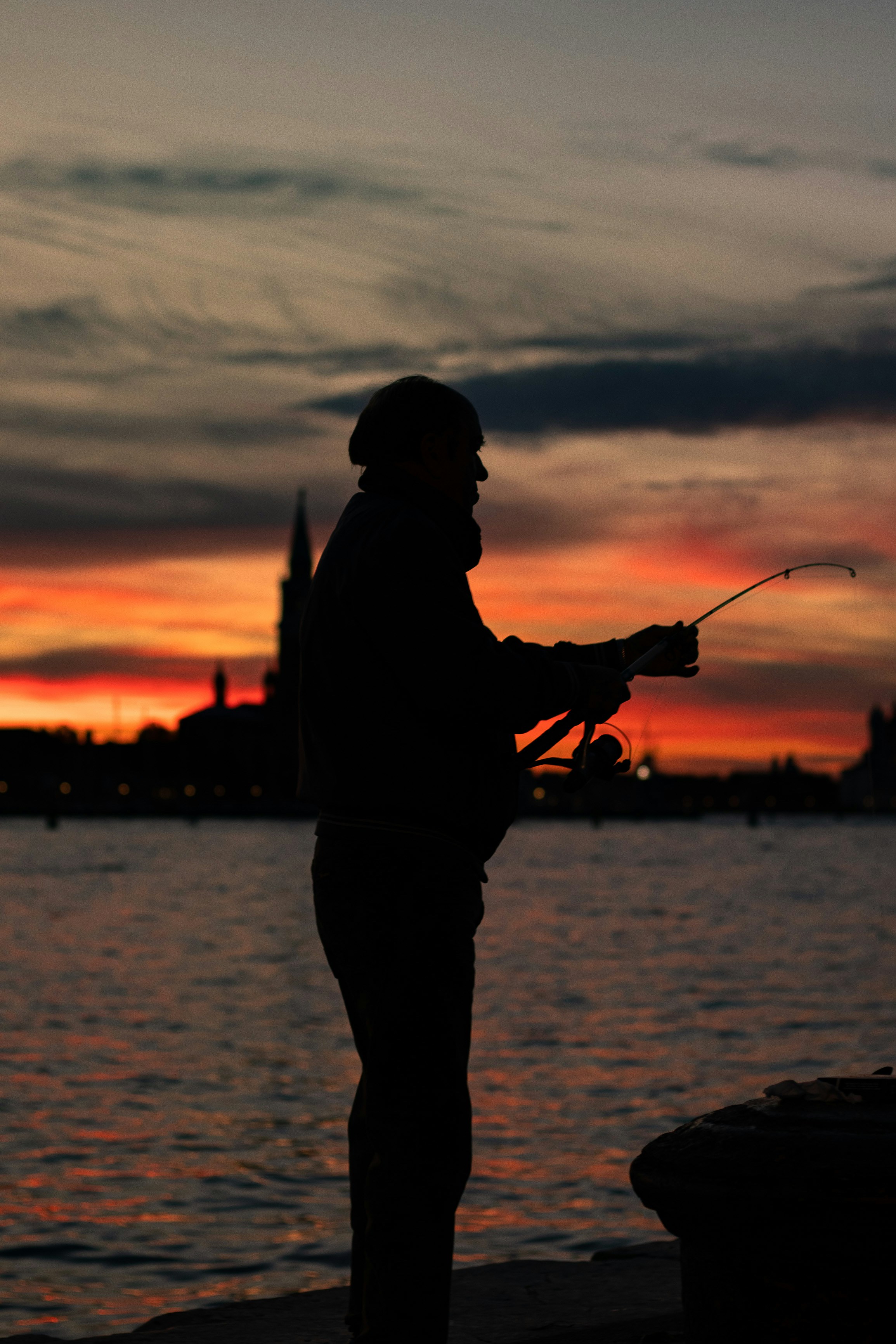 Dusk Casting: A Lone Fisherman Against Ember Skies