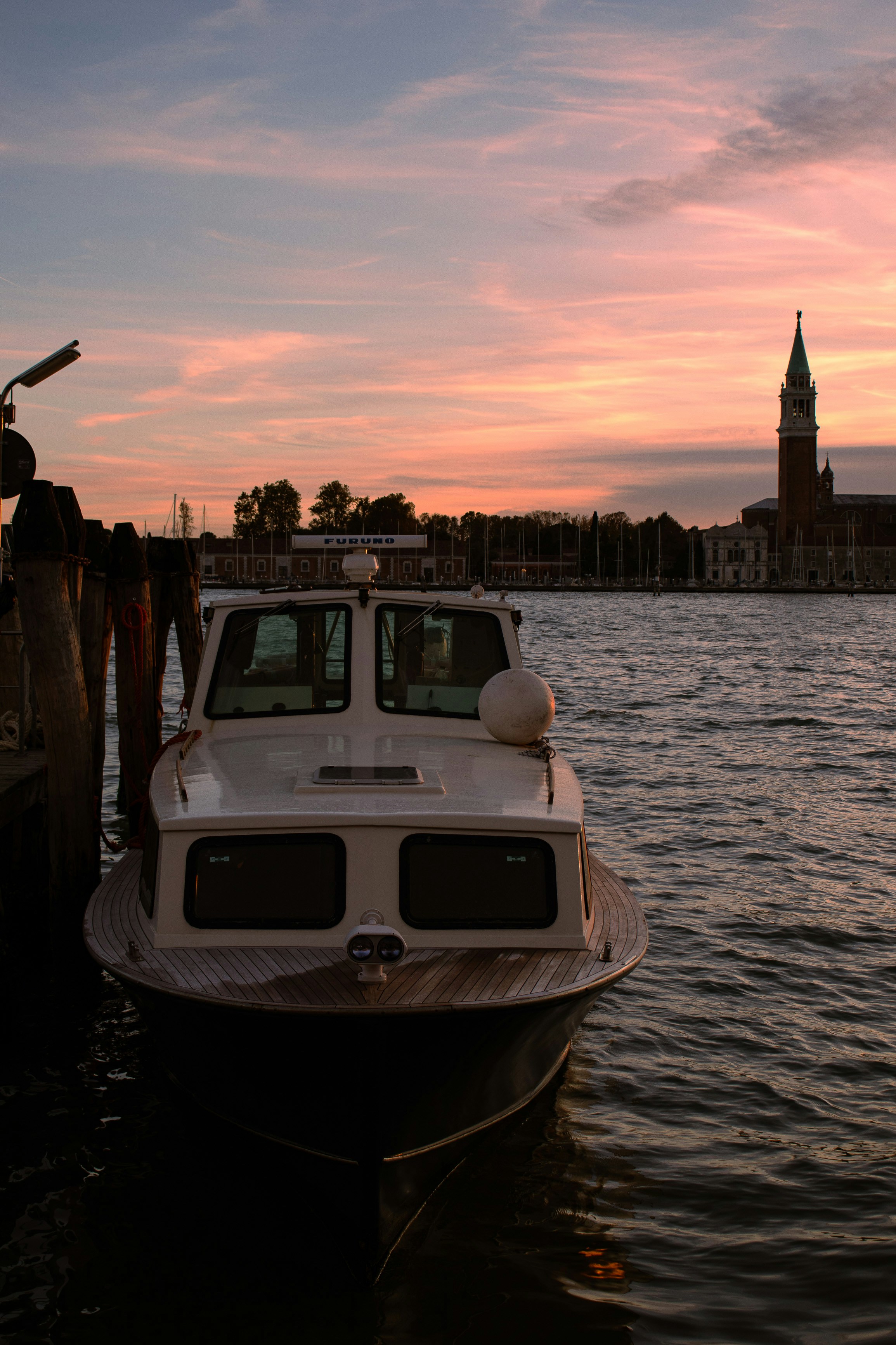 Dusk at the Pier: A White Boat Framed by Sunset and a Distant Clock Tower
