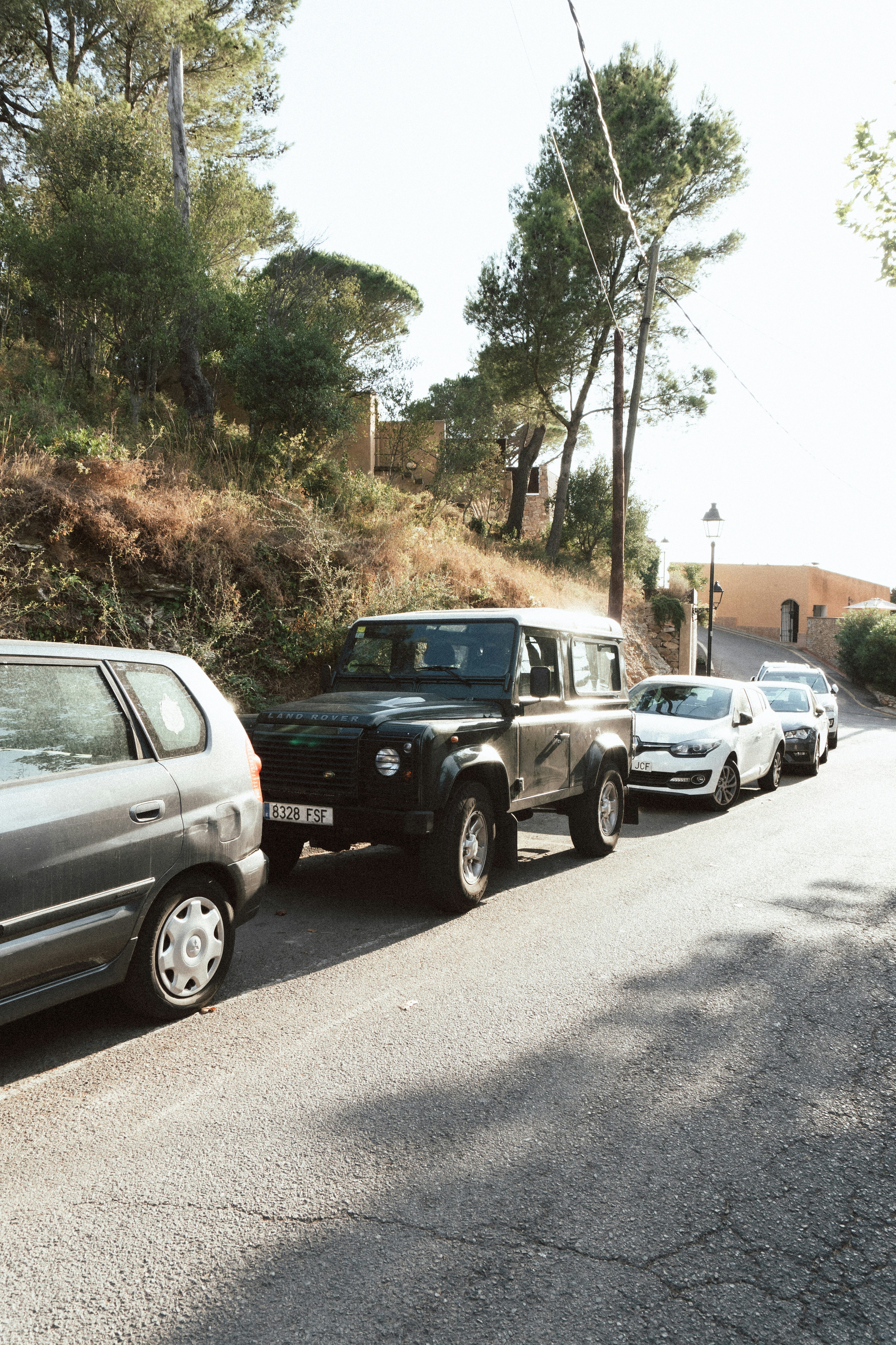 A classic Land Rover defender on the side of the road with a vintage film vibe