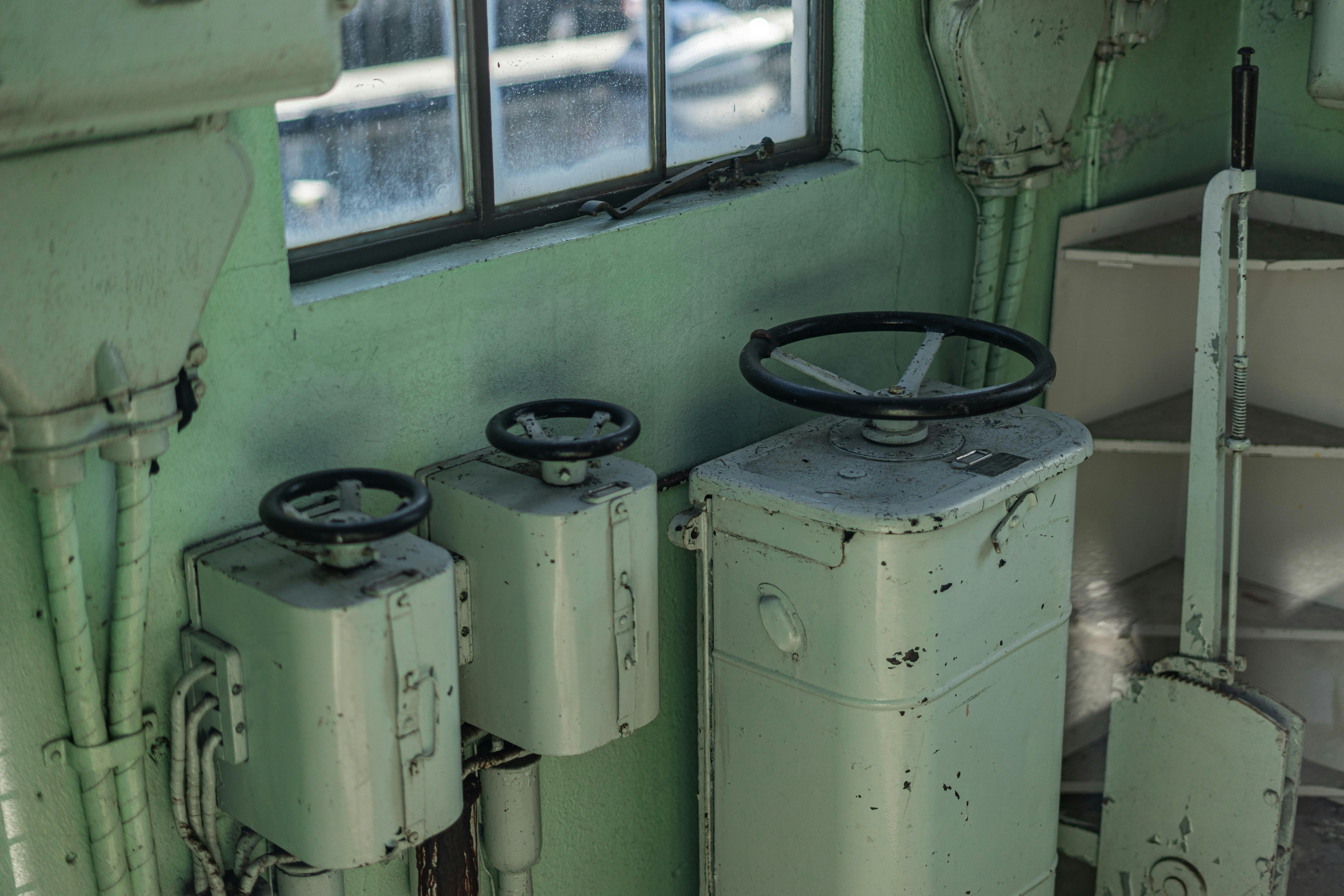 Vintage control panels and valves against a faded green wall, showcasing the remnants of industrial machinery. The scene evokes a sense of nostalgia and history.