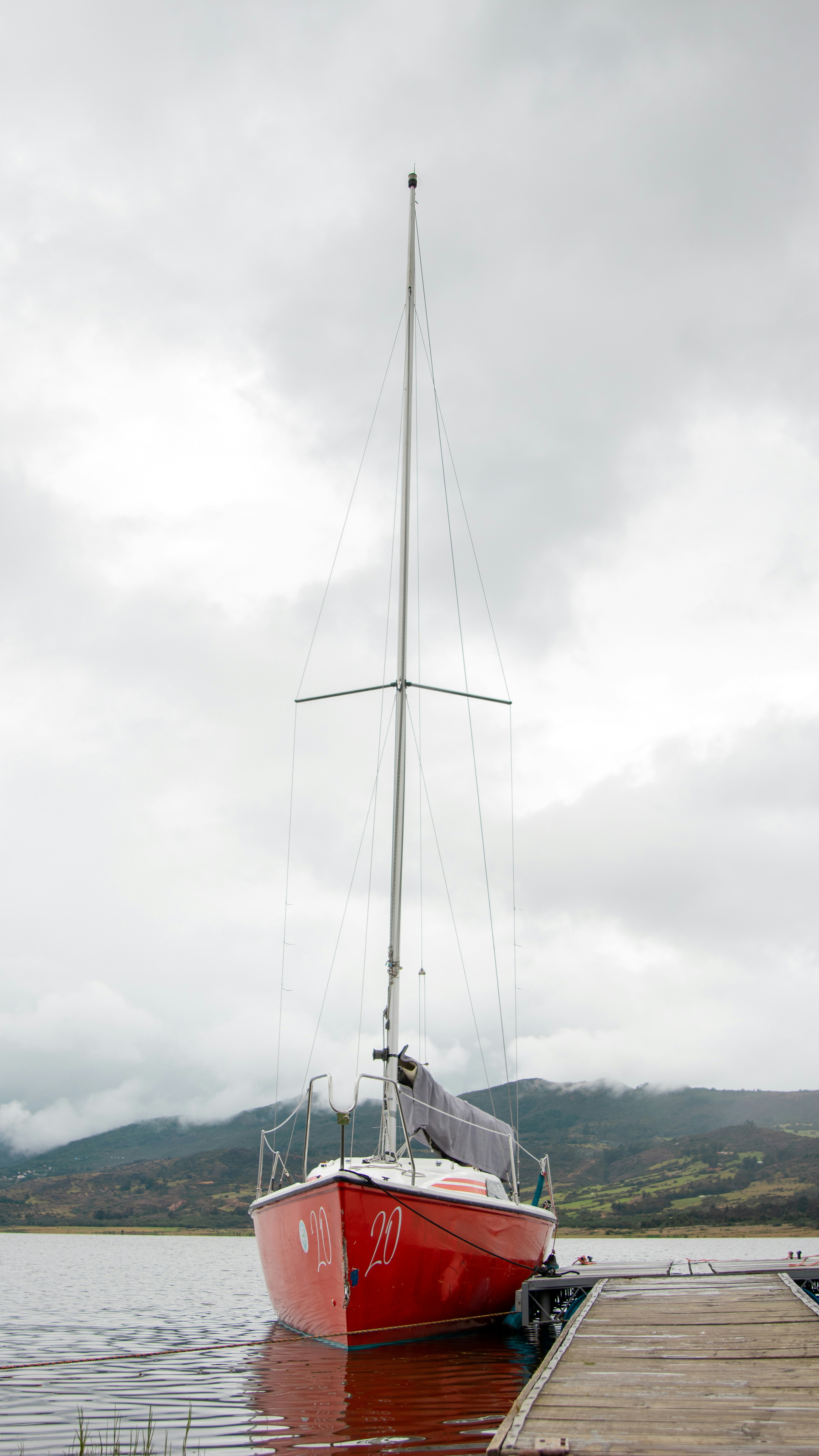 Red Sloop at Rest: A Sailboat Framed by Quiet Waters