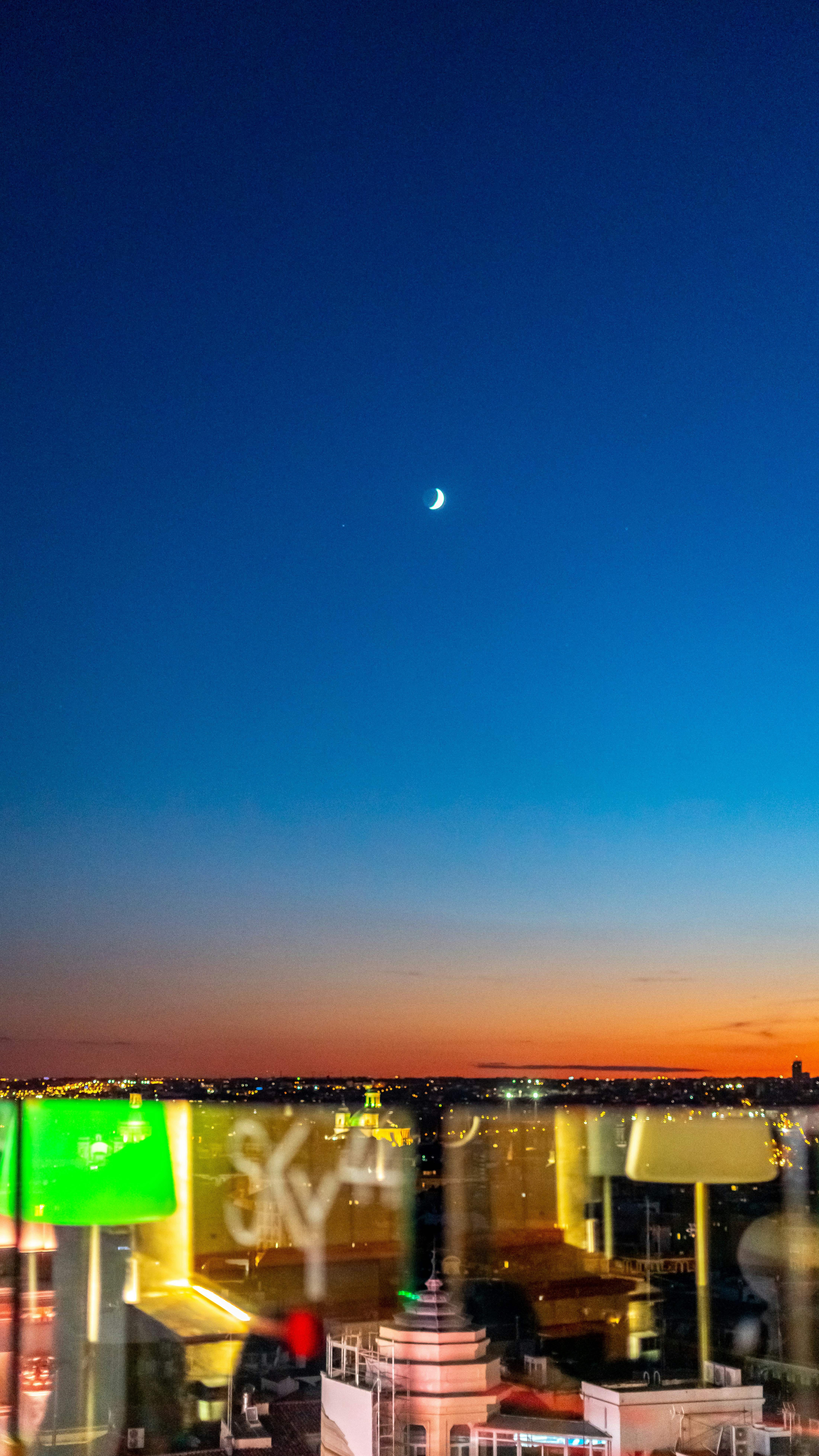 Crescent Over Neon: Dusk Vista from a Glass Balcony