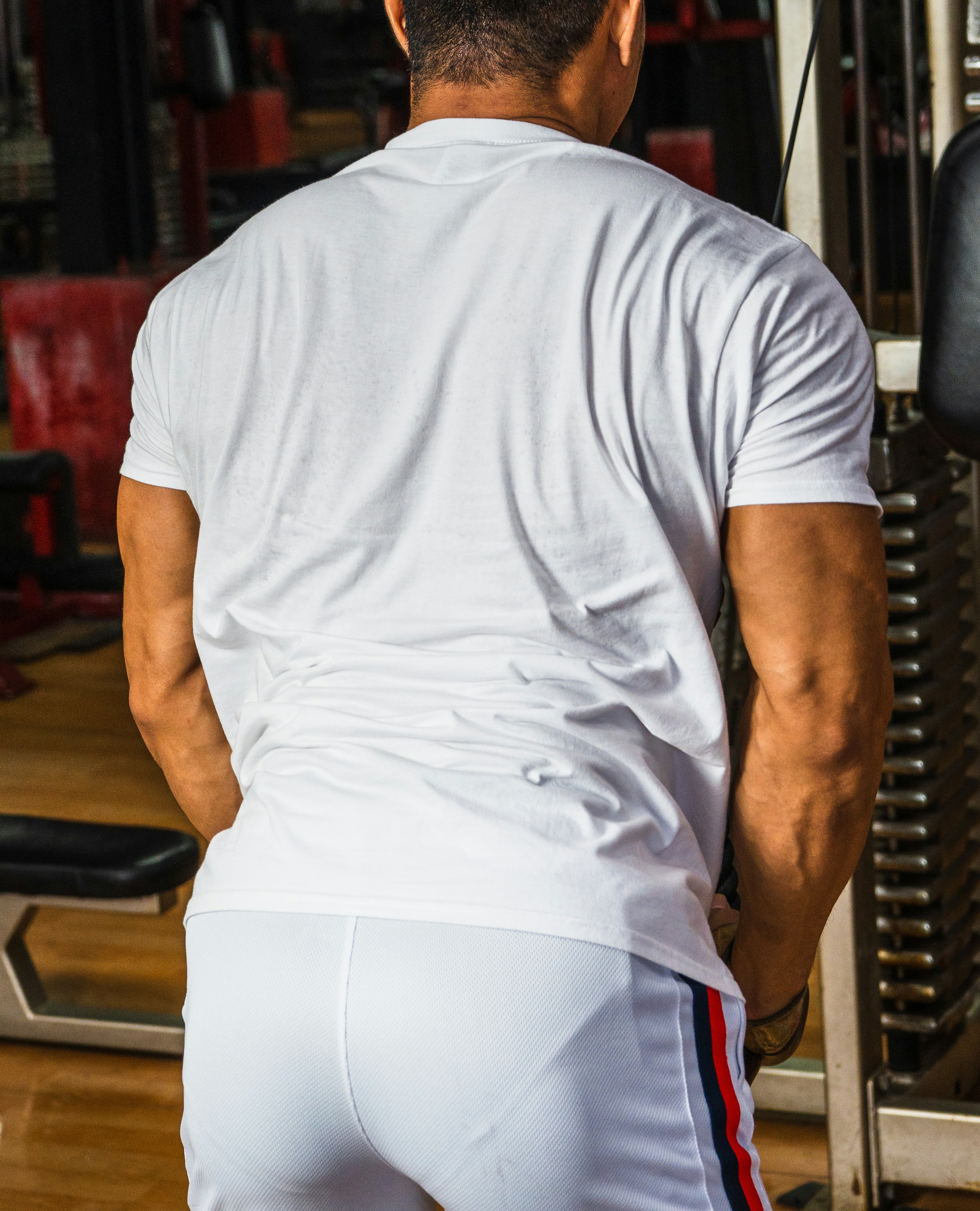 Athlete performing a workout in a gym, showcasing focus and determination while wearing a fitted white shirt and athletic shorts.
