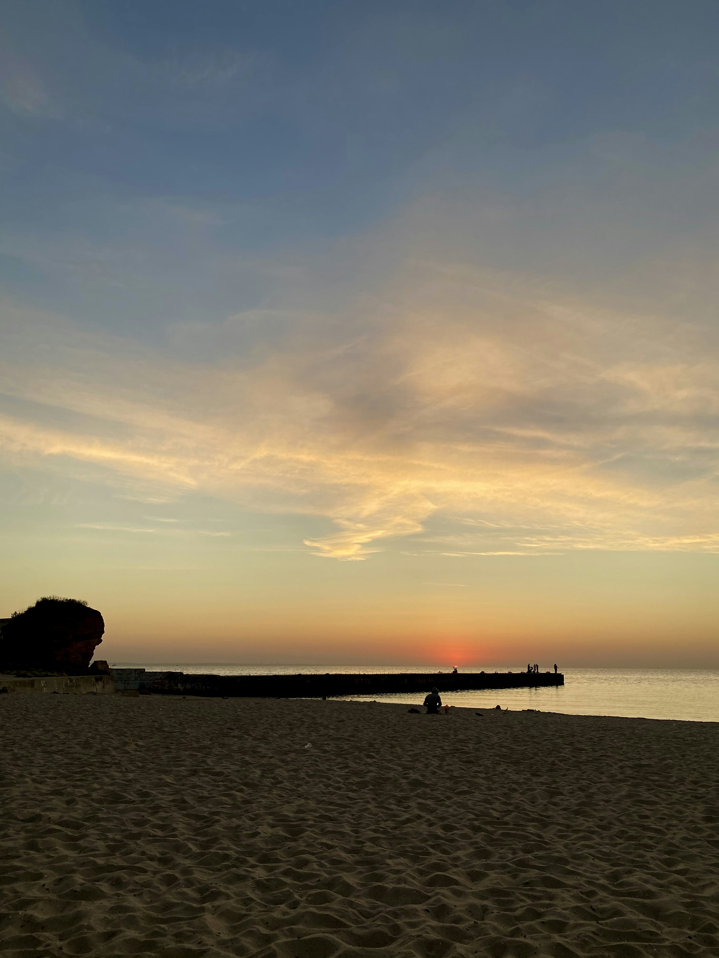 Horizon Ember: Sunset on a Quiet Beach with a Lone Jetty