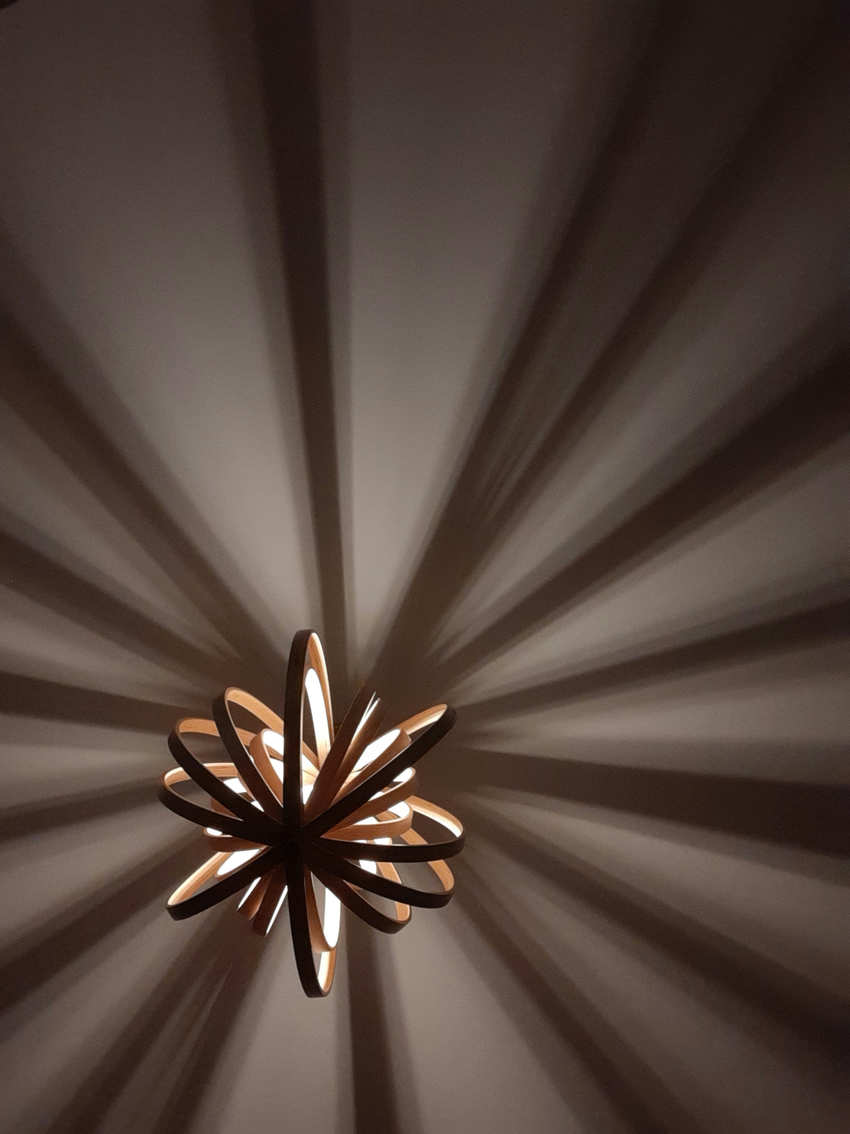 Artistic light fixture casting intricate shadows on the ceiling, creating a dynamic interplay of light and form.