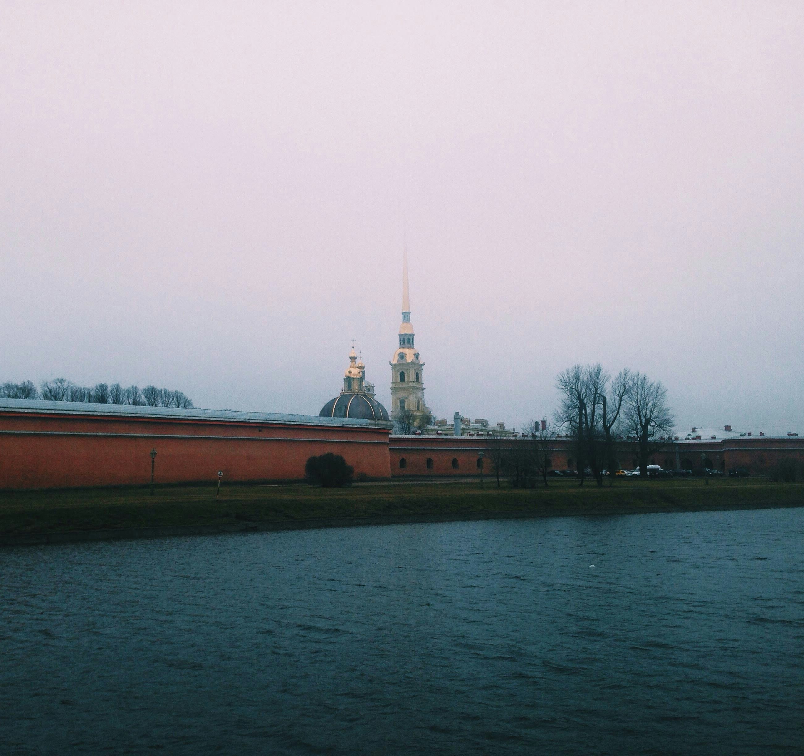 Historic architecture emerges from a misty backdrop, with a tranquil river flowing in the foreground. The scene evokes a sense of calm and nostalgia.