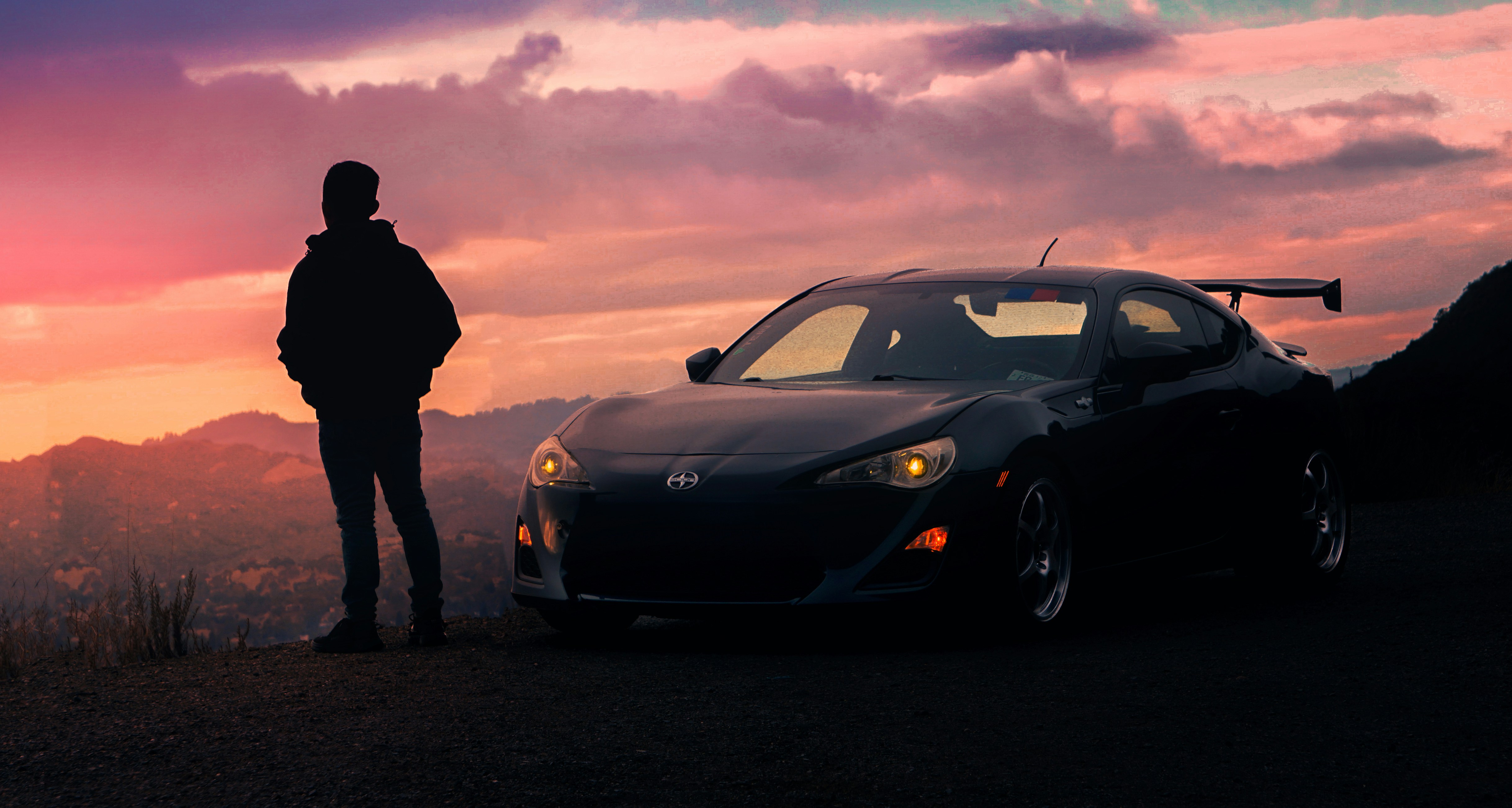 Silhouette and Sport: A Sunset Standby beside a Sleek Contender