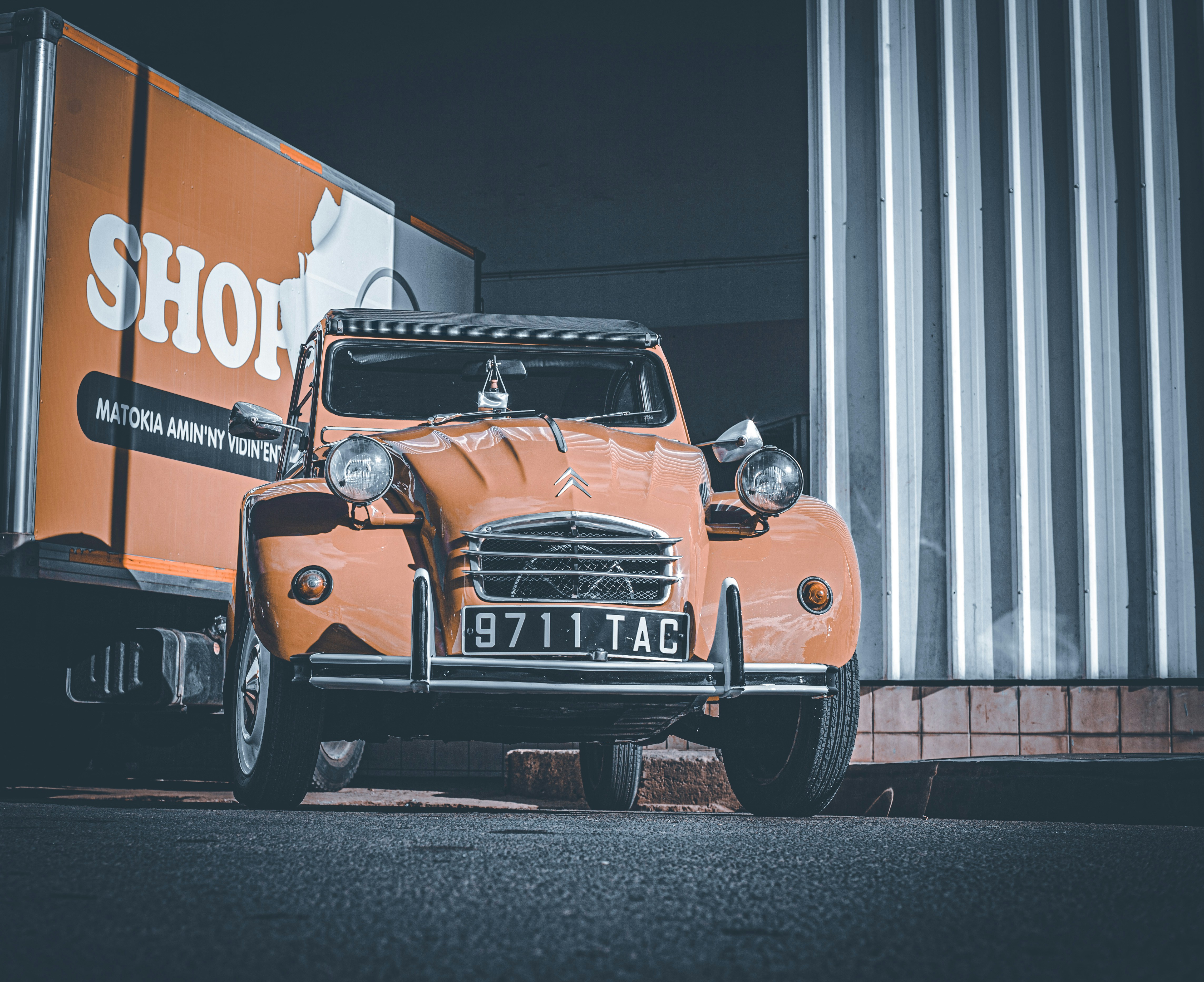 Orange vintage truck under industrial lines: a quiet street-side scene
