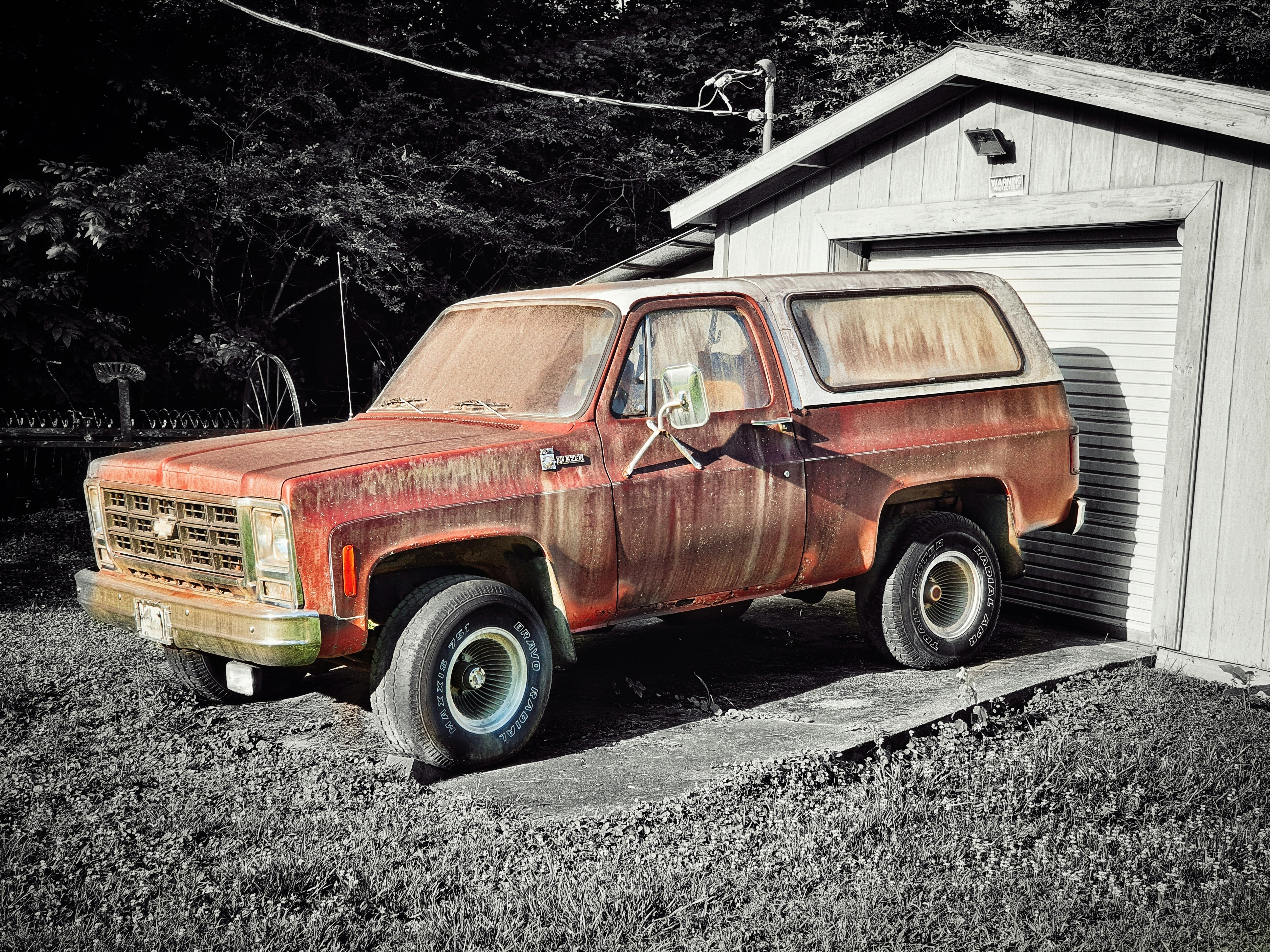 Vintage truck with rusted exterior parked beside a shed, showcasing the passage of time and decay.