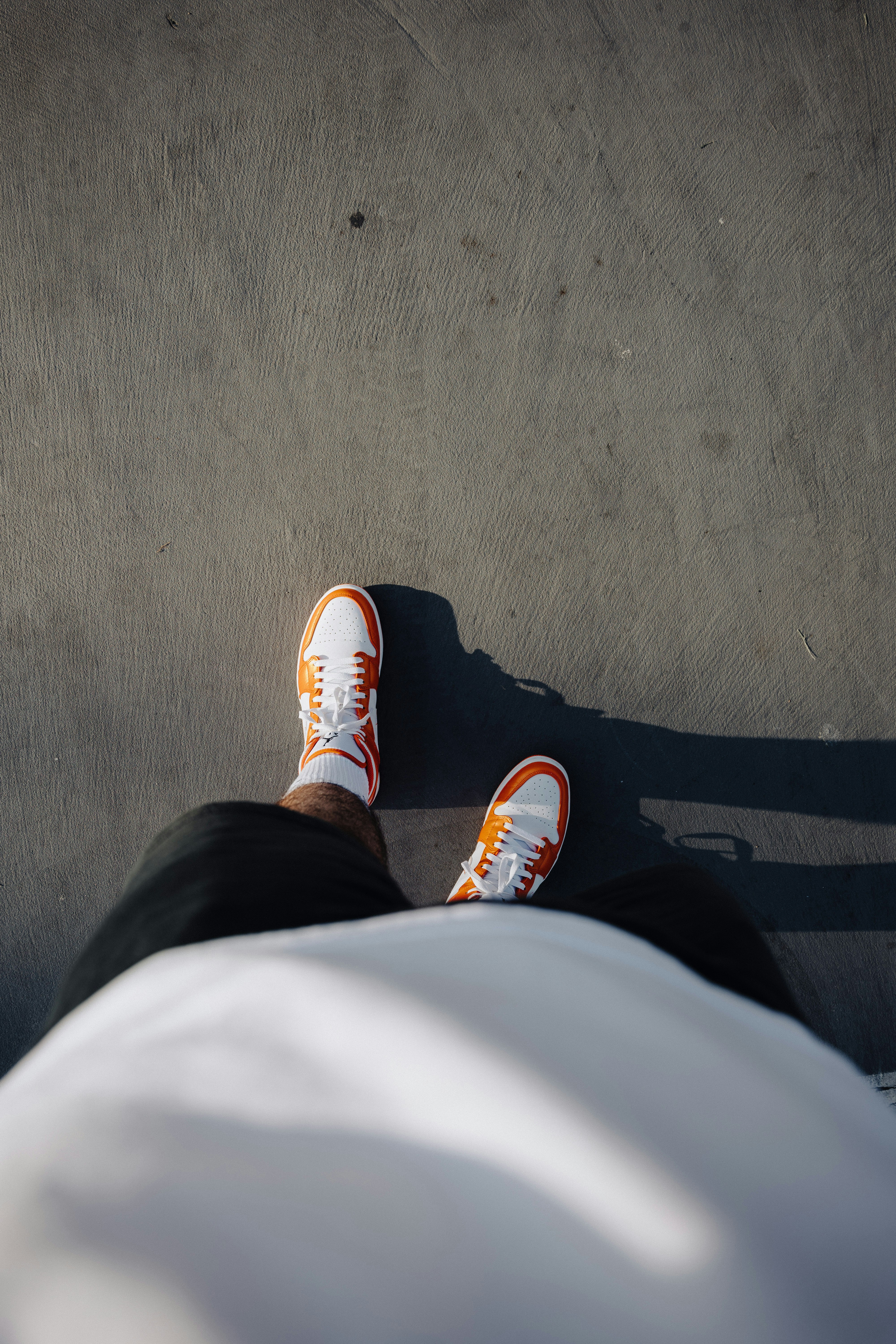 Aerial view of a person’s feet in stylish sneakers on a textured surface, suggesting an urban exploration theme.