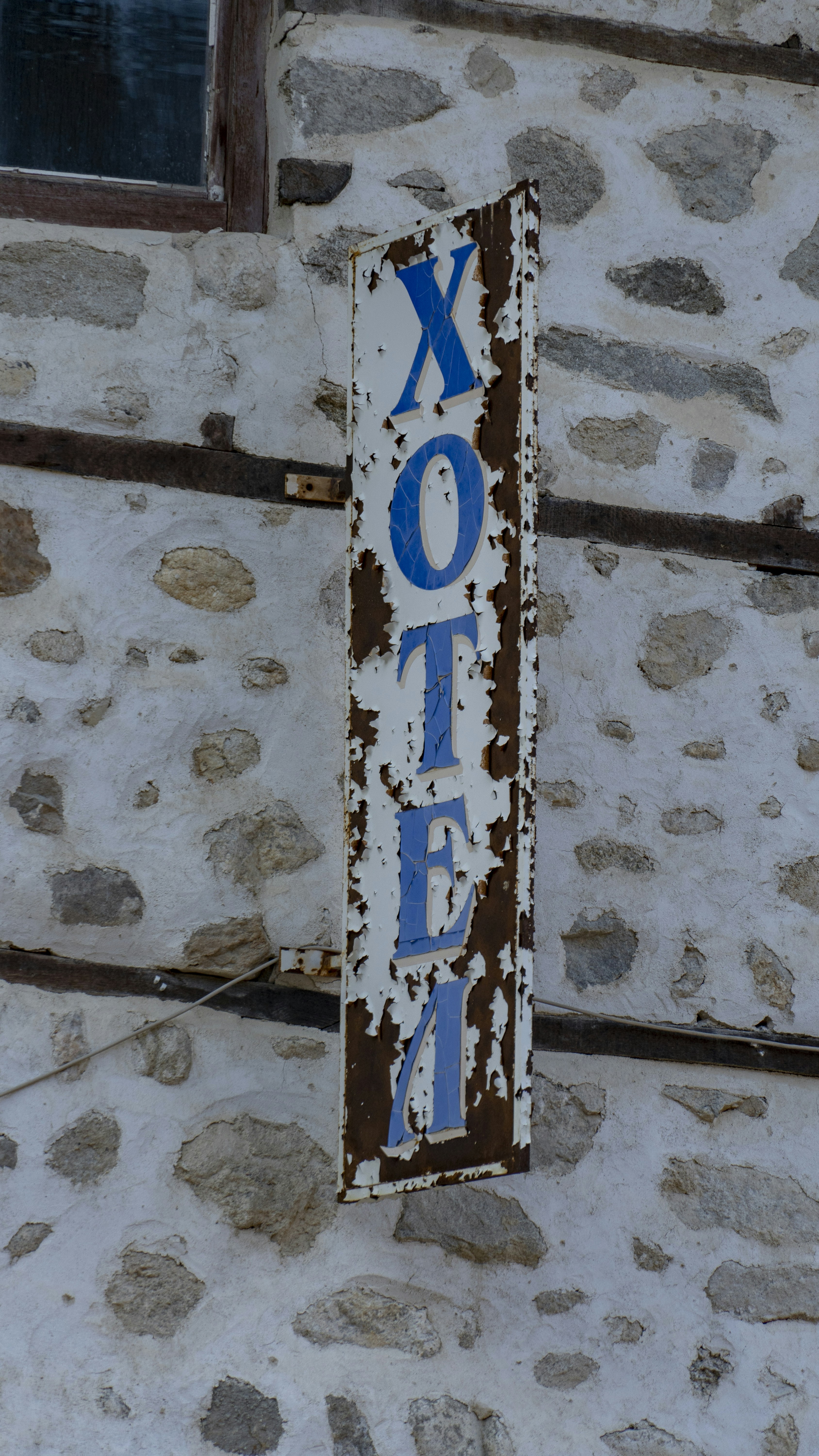 Vertical Signage of an Old Hotel Imperfectly Painted Blue Letters