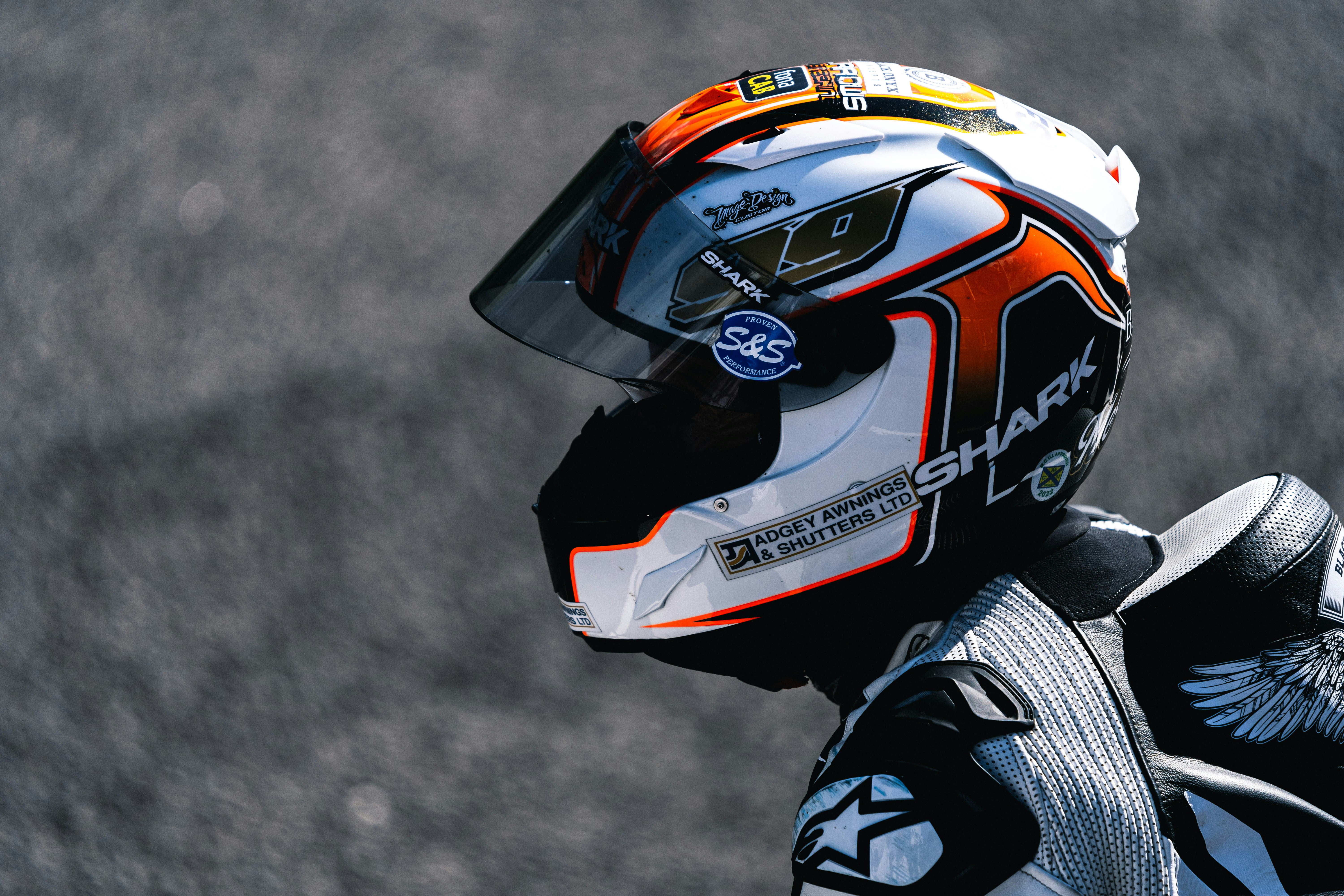 Close-up of a motorcycle helmet adorned with sponsor logos, capturing the intense focus of a rider gearing up for the race.