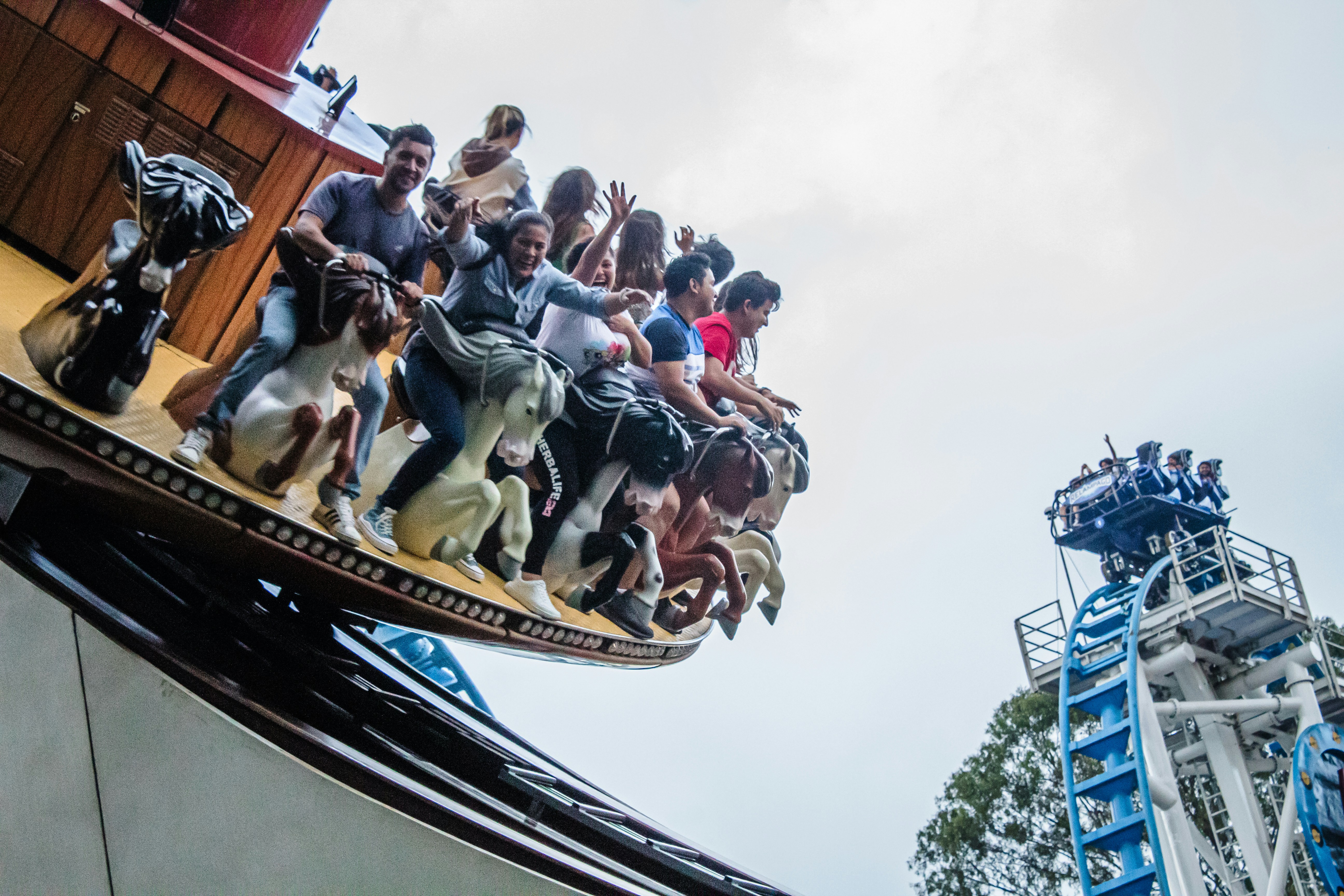 People experiencing a high-speed ride on a roller coaster, with a backdrop of cloudy sky.