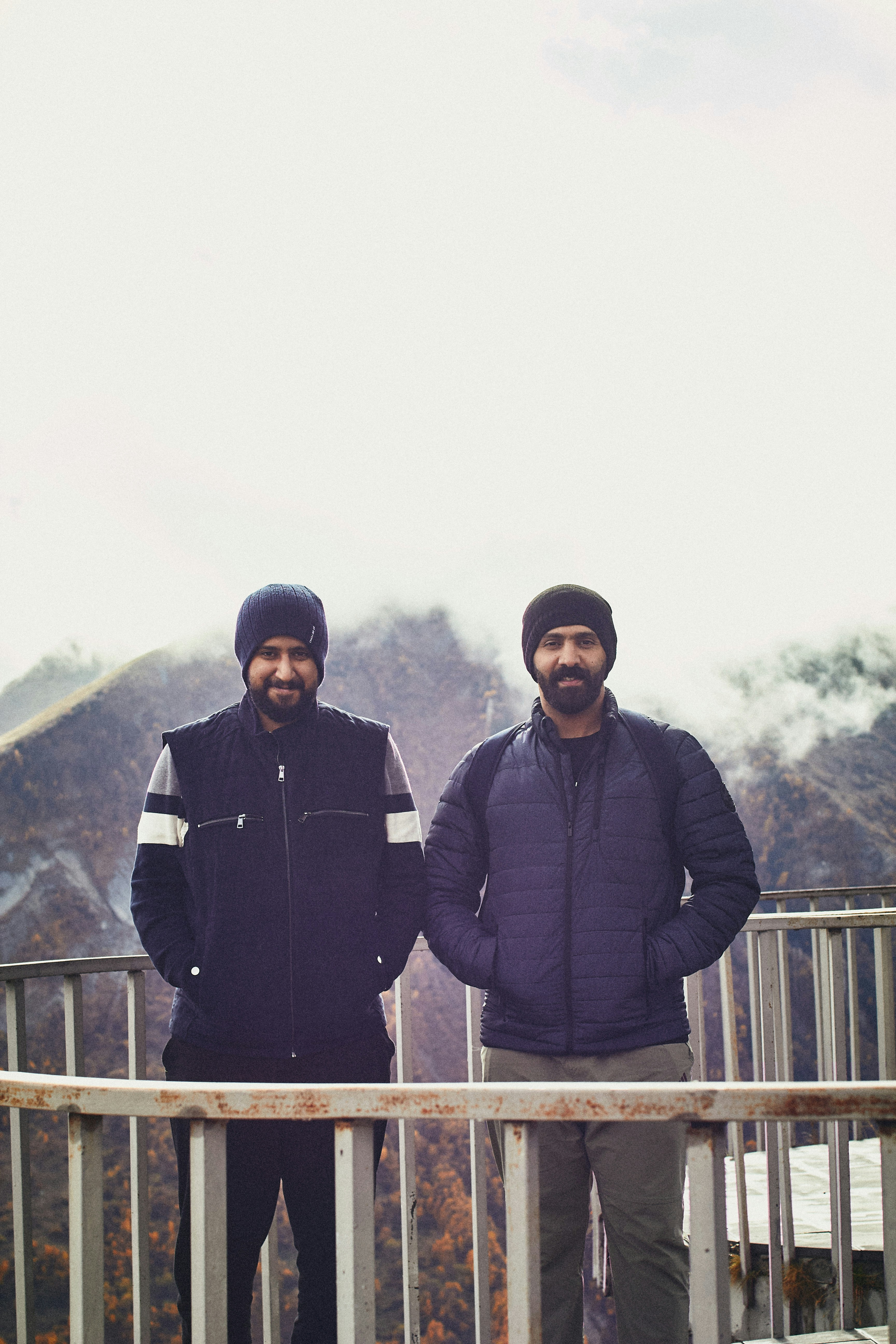 Two men standing on a bridge photo – Free Coat Image on Unsplash