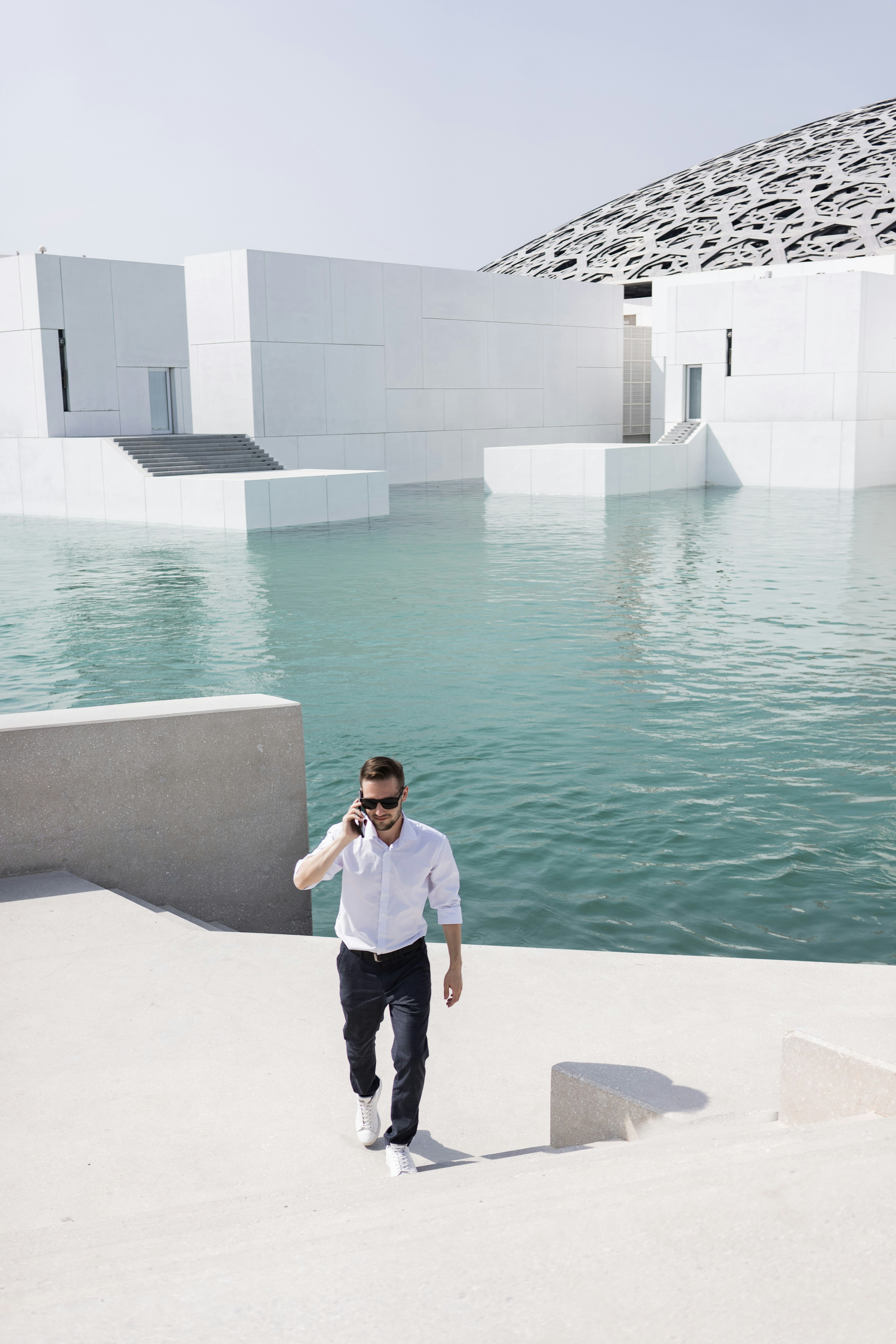 Stride and Sea: A man in white shirts walks along white steps beside turquoise water