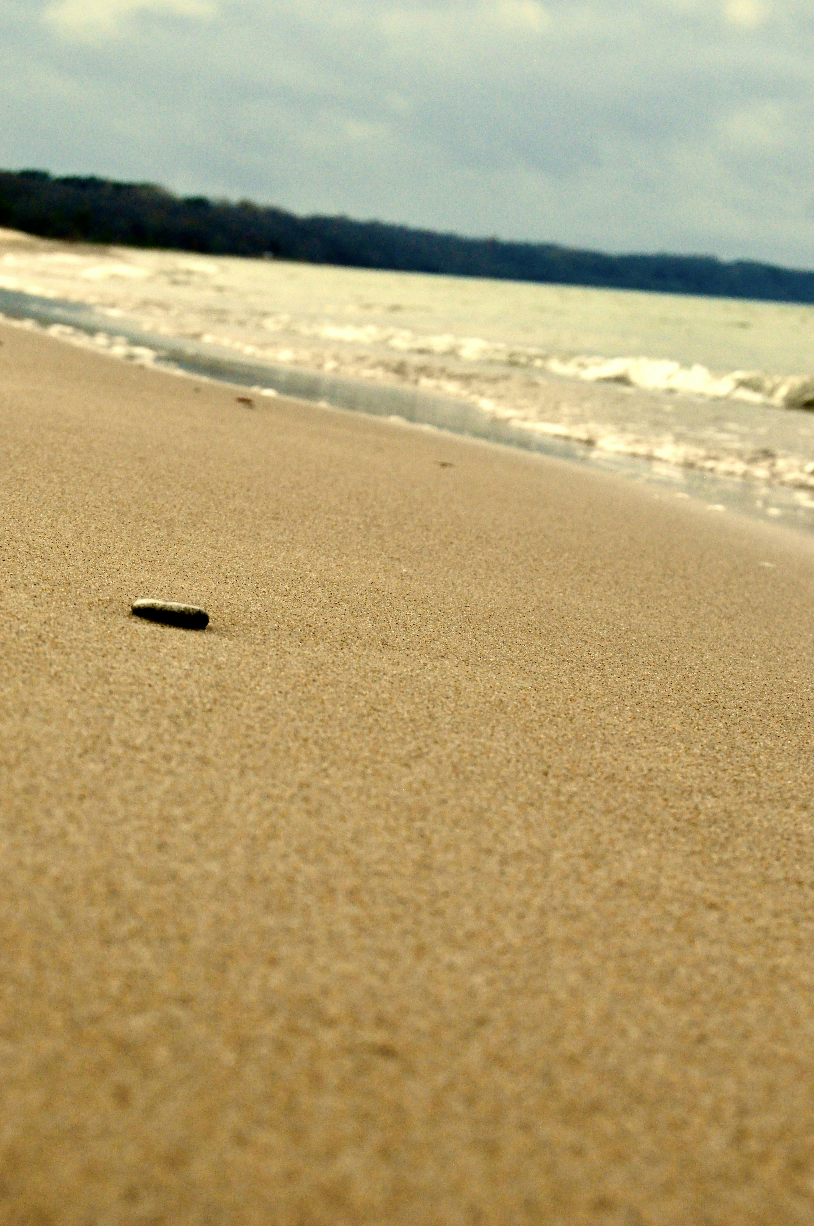 Lone Pebble on a Golden Beach under Soft Clouds