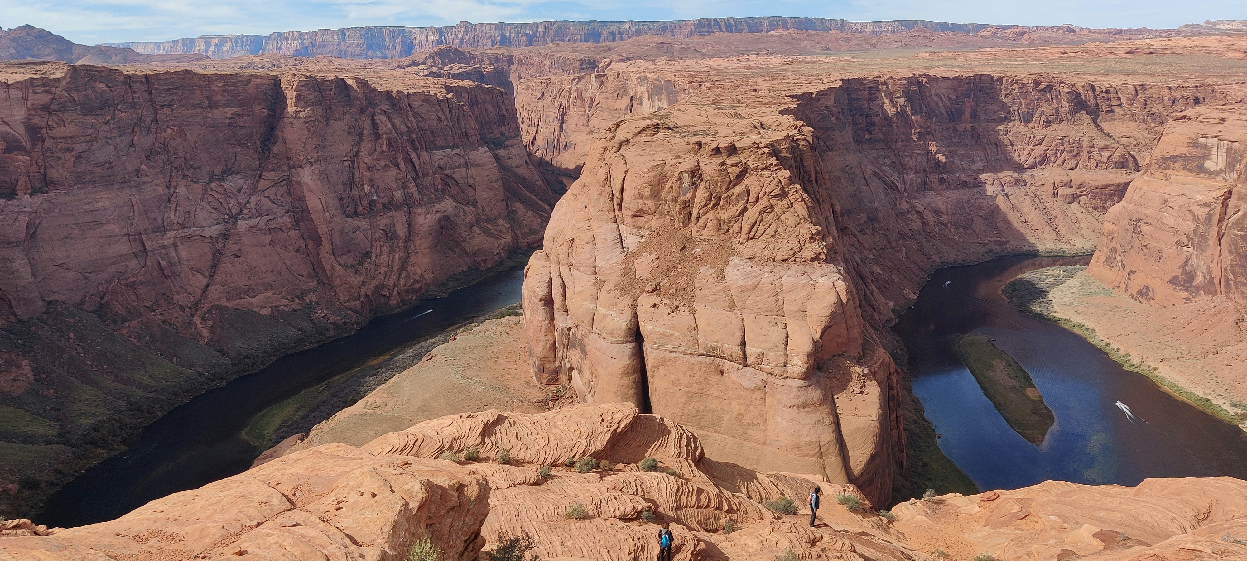 Vast red rock formations frame the winding curves of the Colorado River at Horseshoe Bend, showcasing the dramatic interplay of nature's artistry.