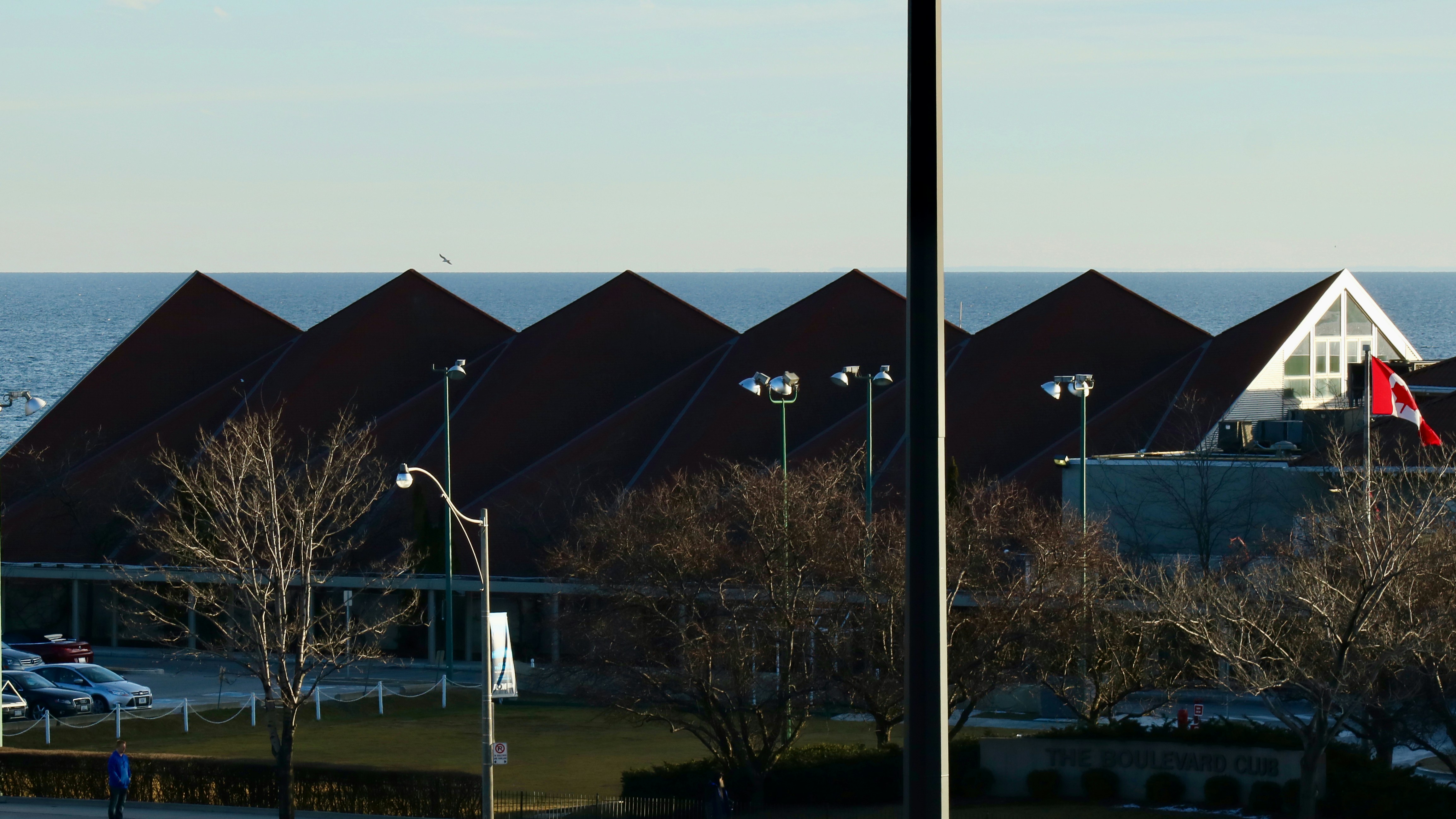 Row of sawtooth roofs framed by a lone lamp on the seafront