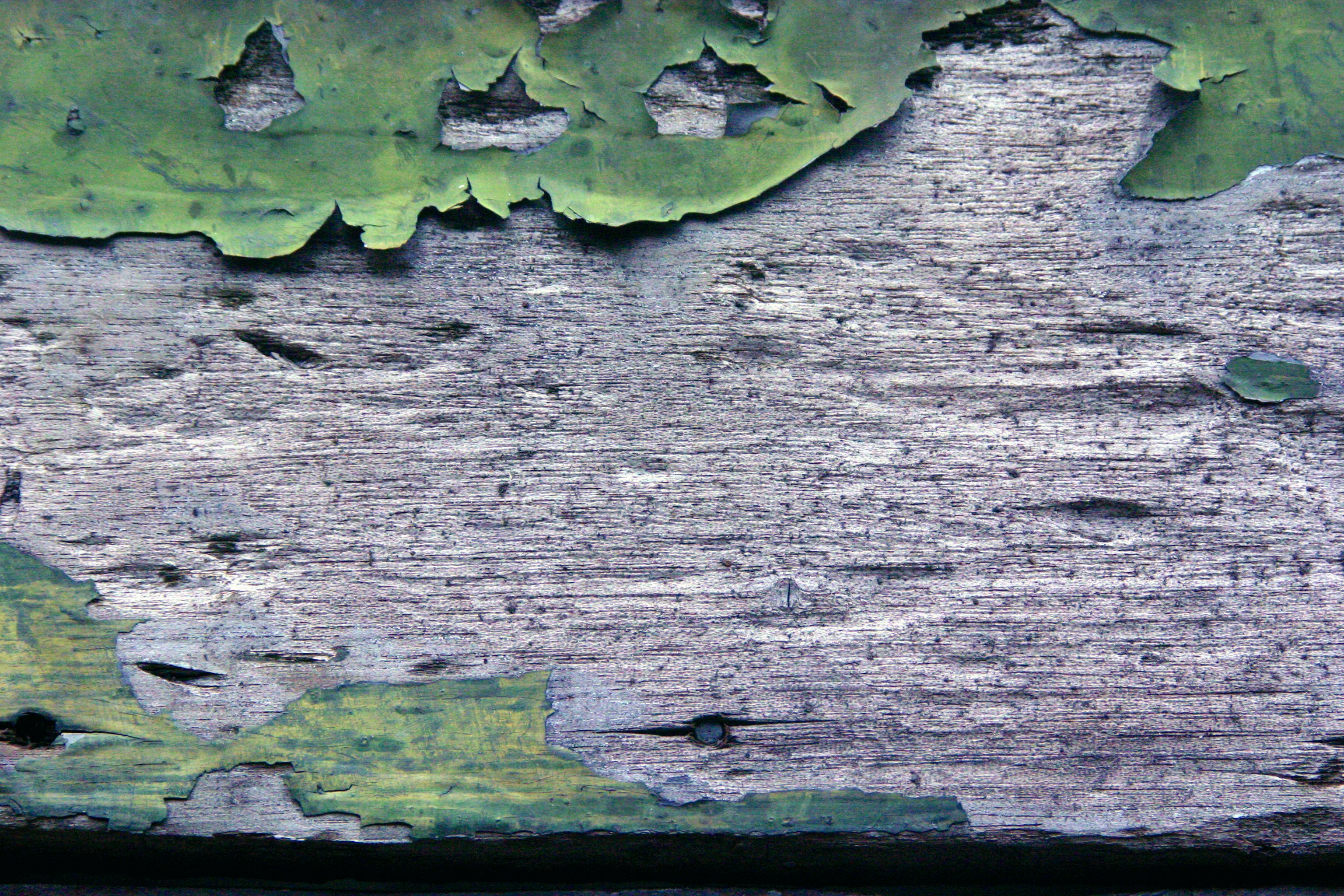 Peeling green paint on a wood plank.