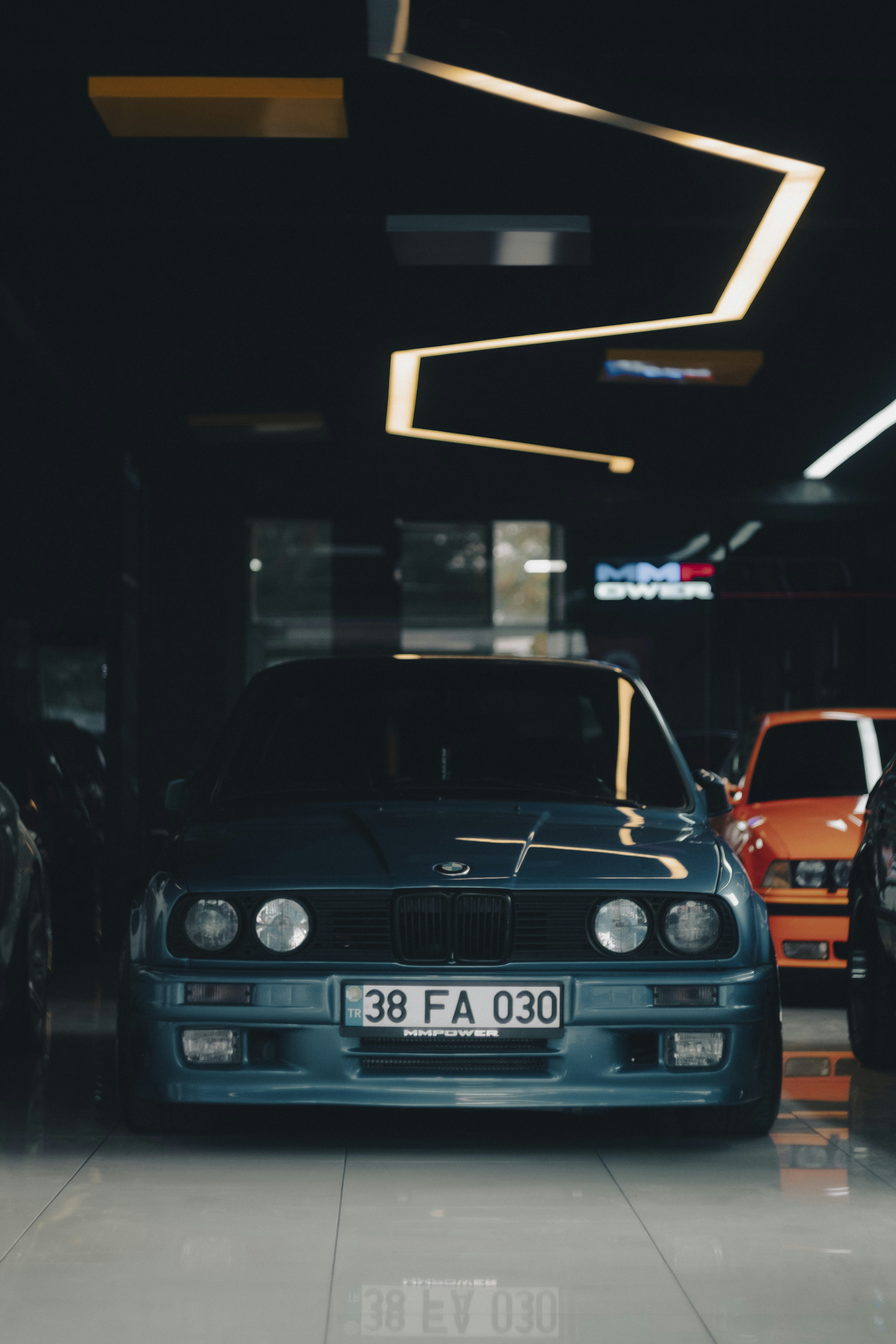 Blue BMW Under Neon Zigzag Lights in a Quiet Showroom